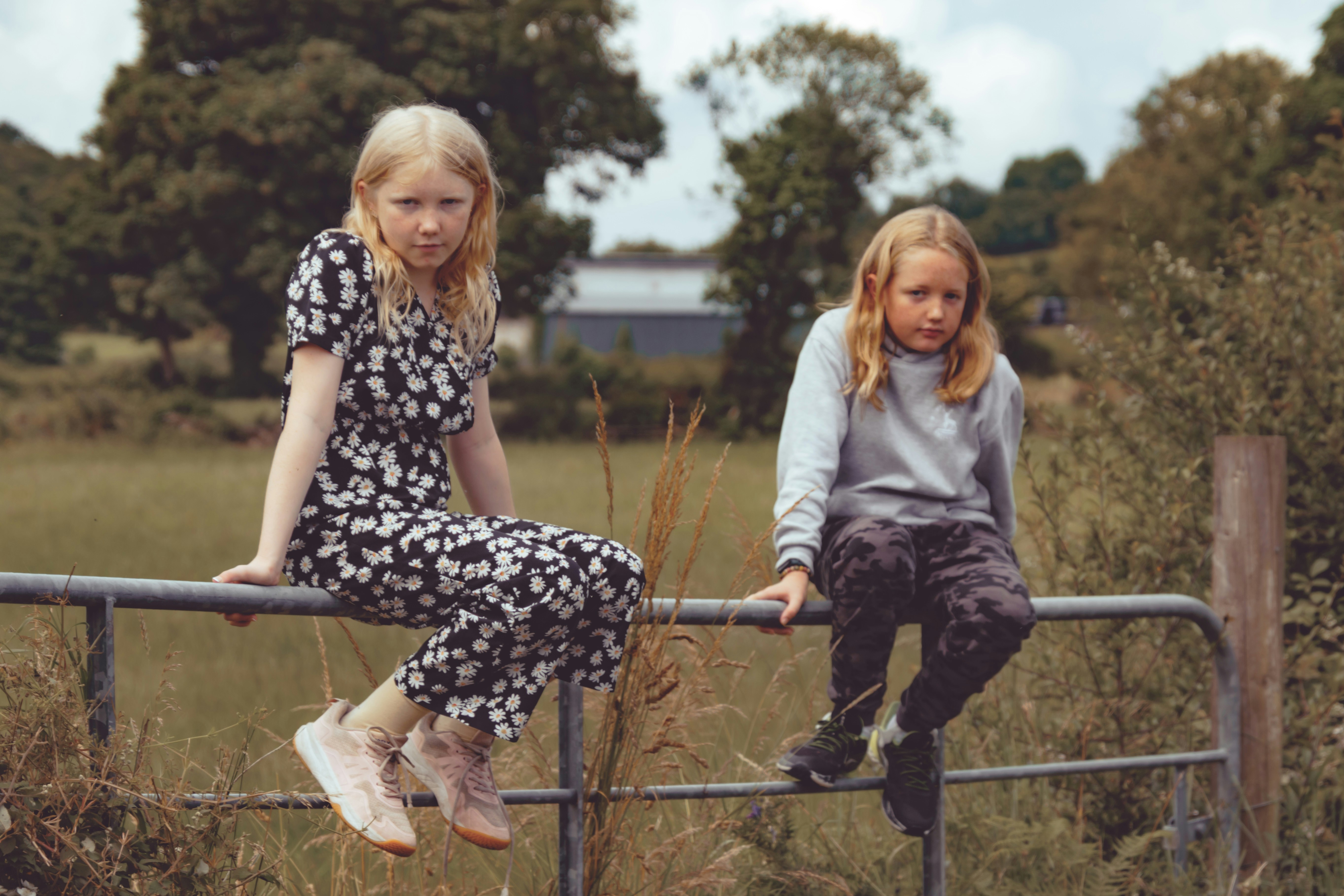 Paused atop the Rails: Twin Girls in a Quiet Field