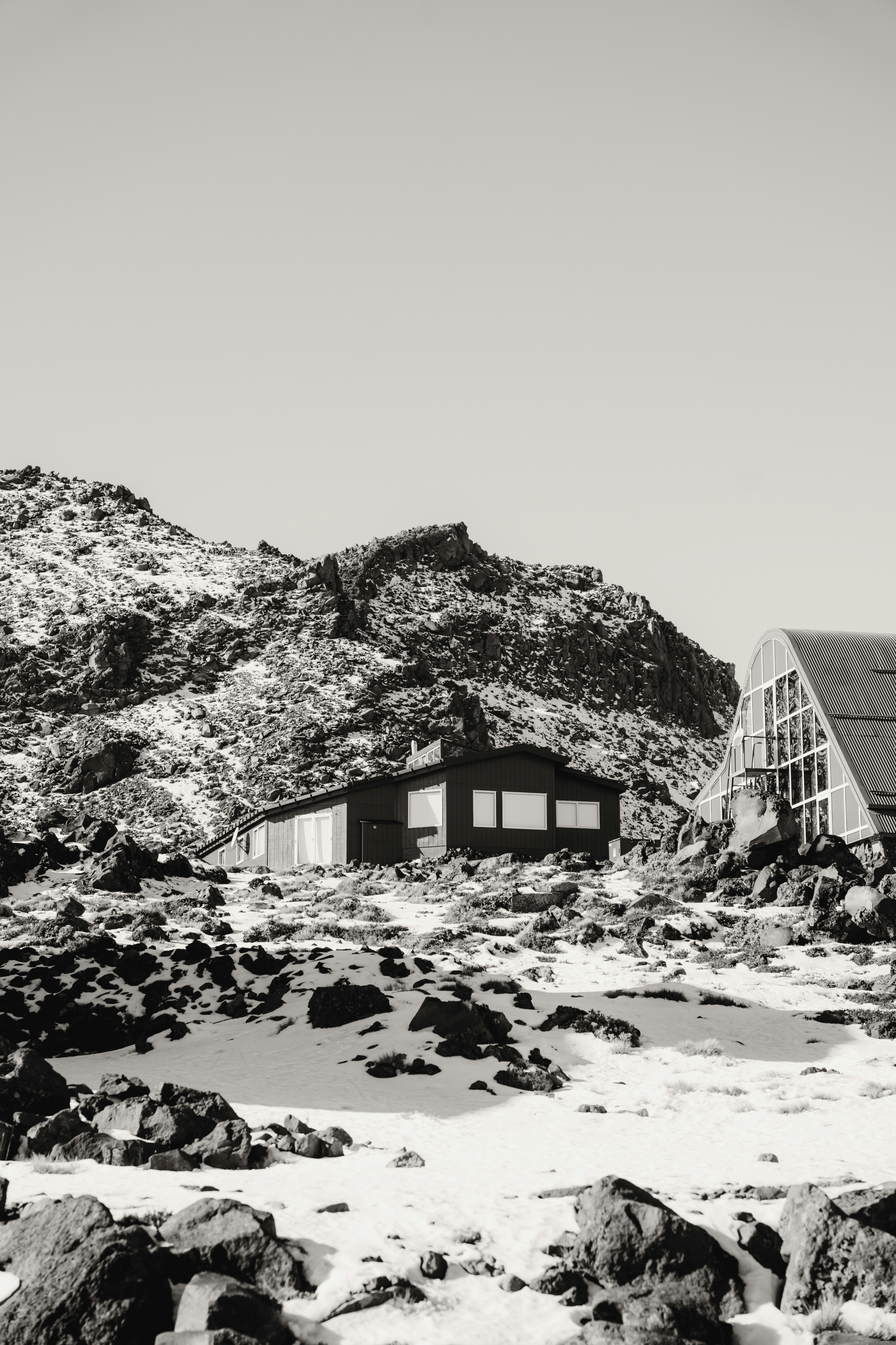 Snowbound Outpost Between Jagged Rocks and a Glasshouse