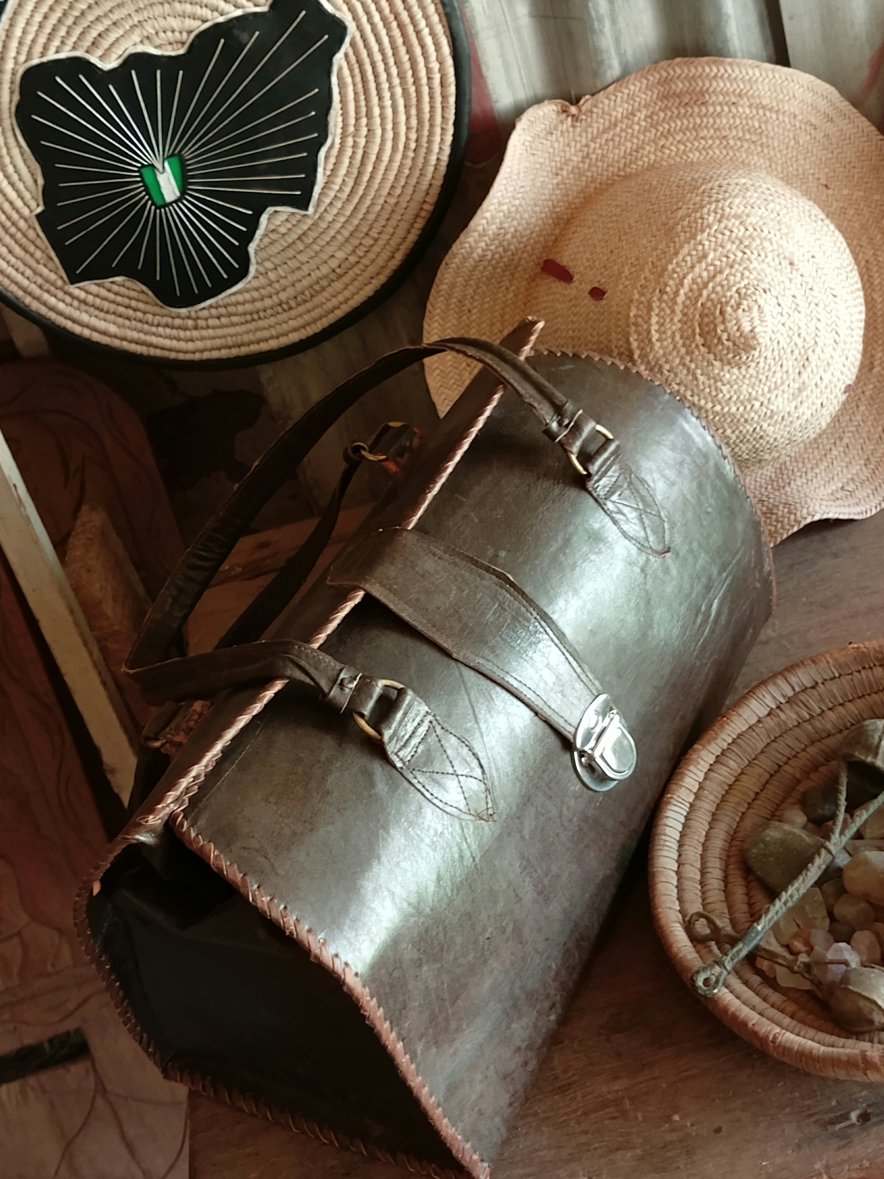 Threads of Time: A Leather Satchel Resting Amid Rustic Straw Hats