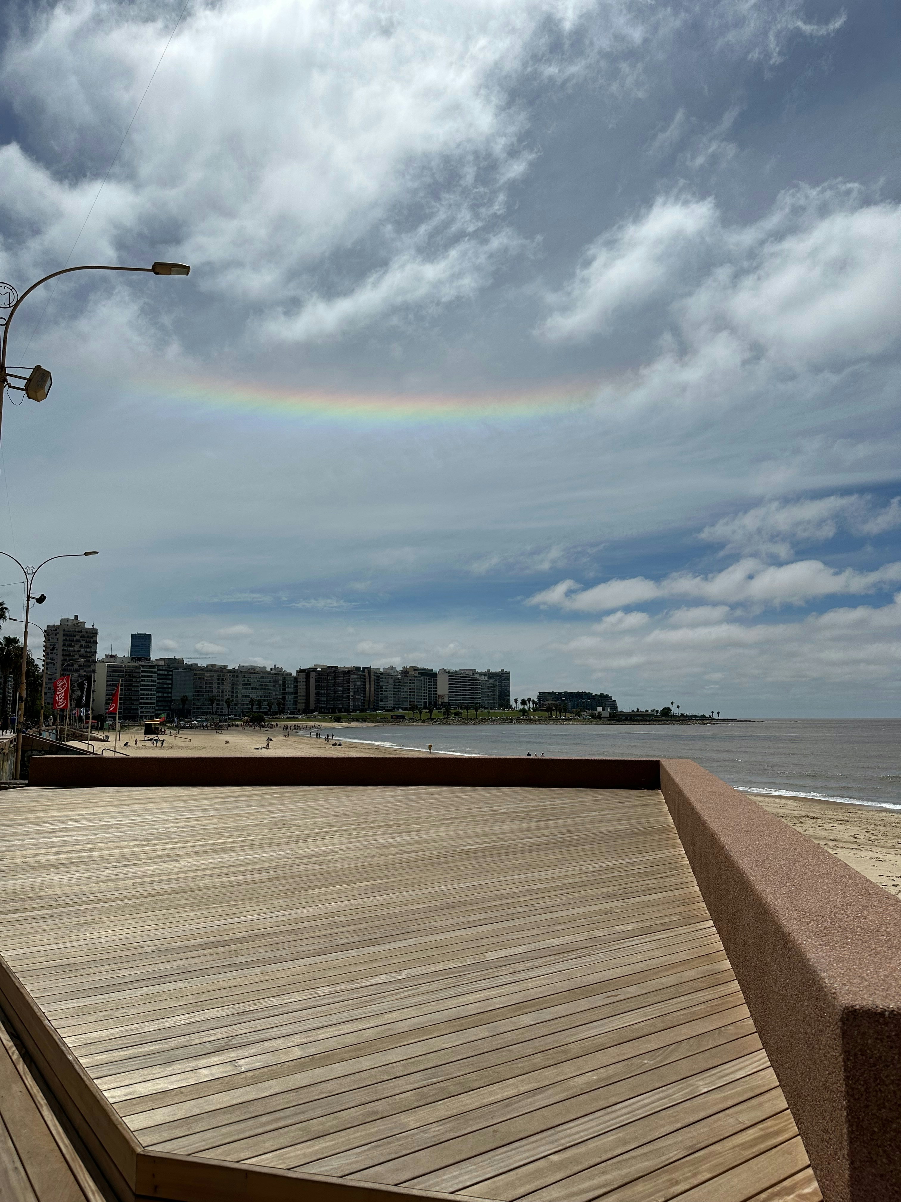 Rainbow Over the Modern Coastal Promenade: Wood Decks, Streetlights, and Sea