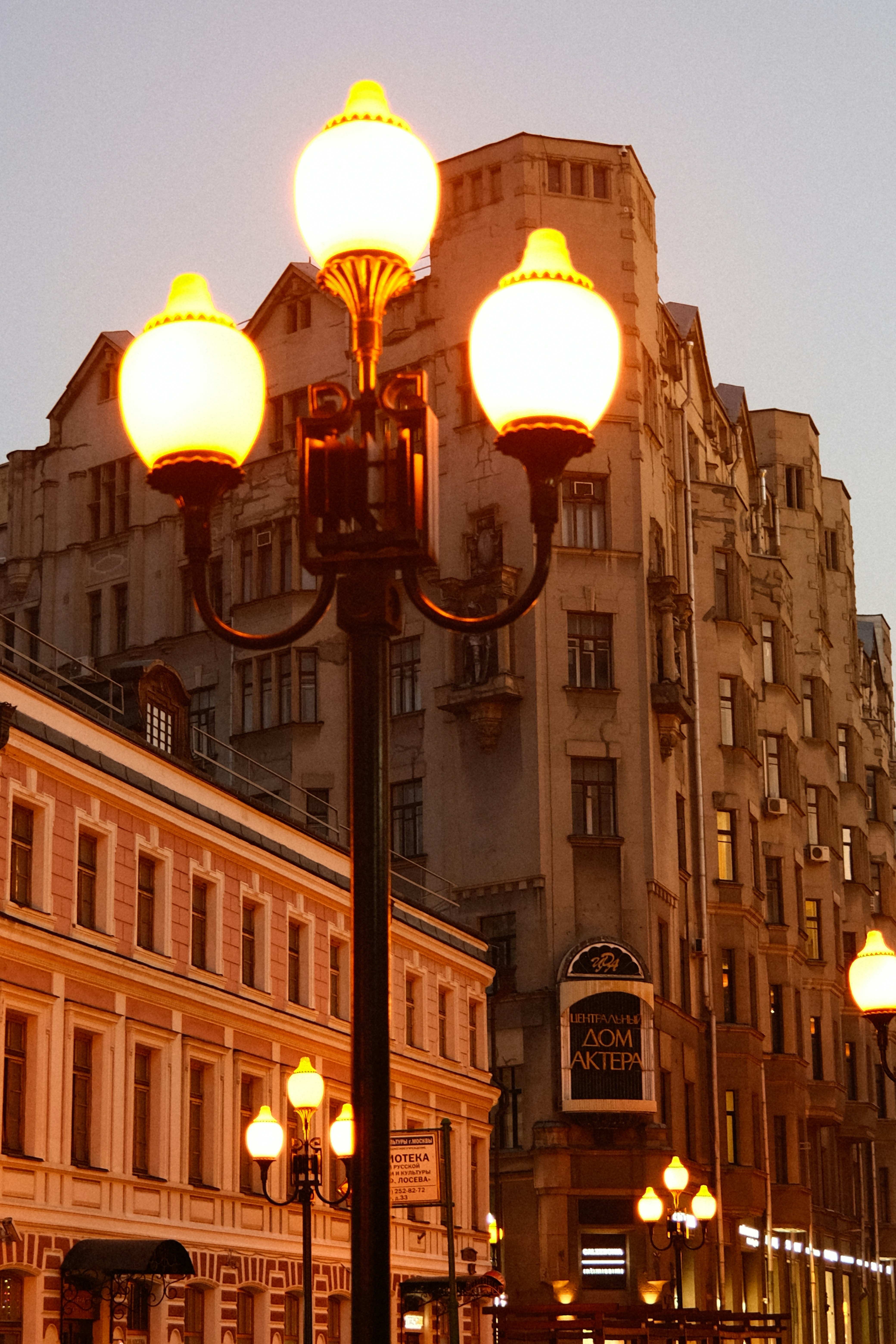 Amber-Globed Streetlamp Trio Casts a Warm Halo Across a Historic City Street