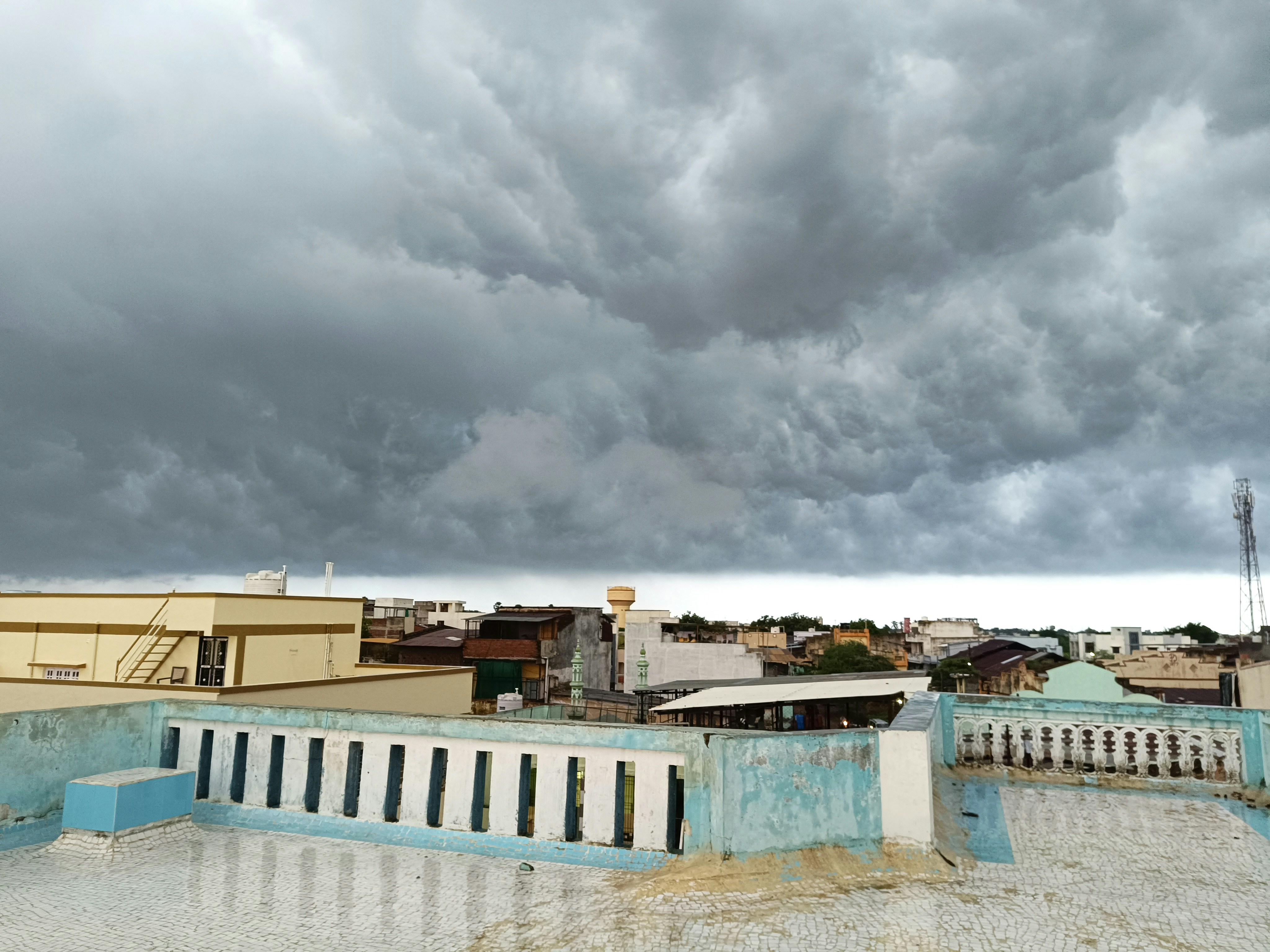Thunder Over Terrace: Turquoise Rooftops Beneath a Looming Sky