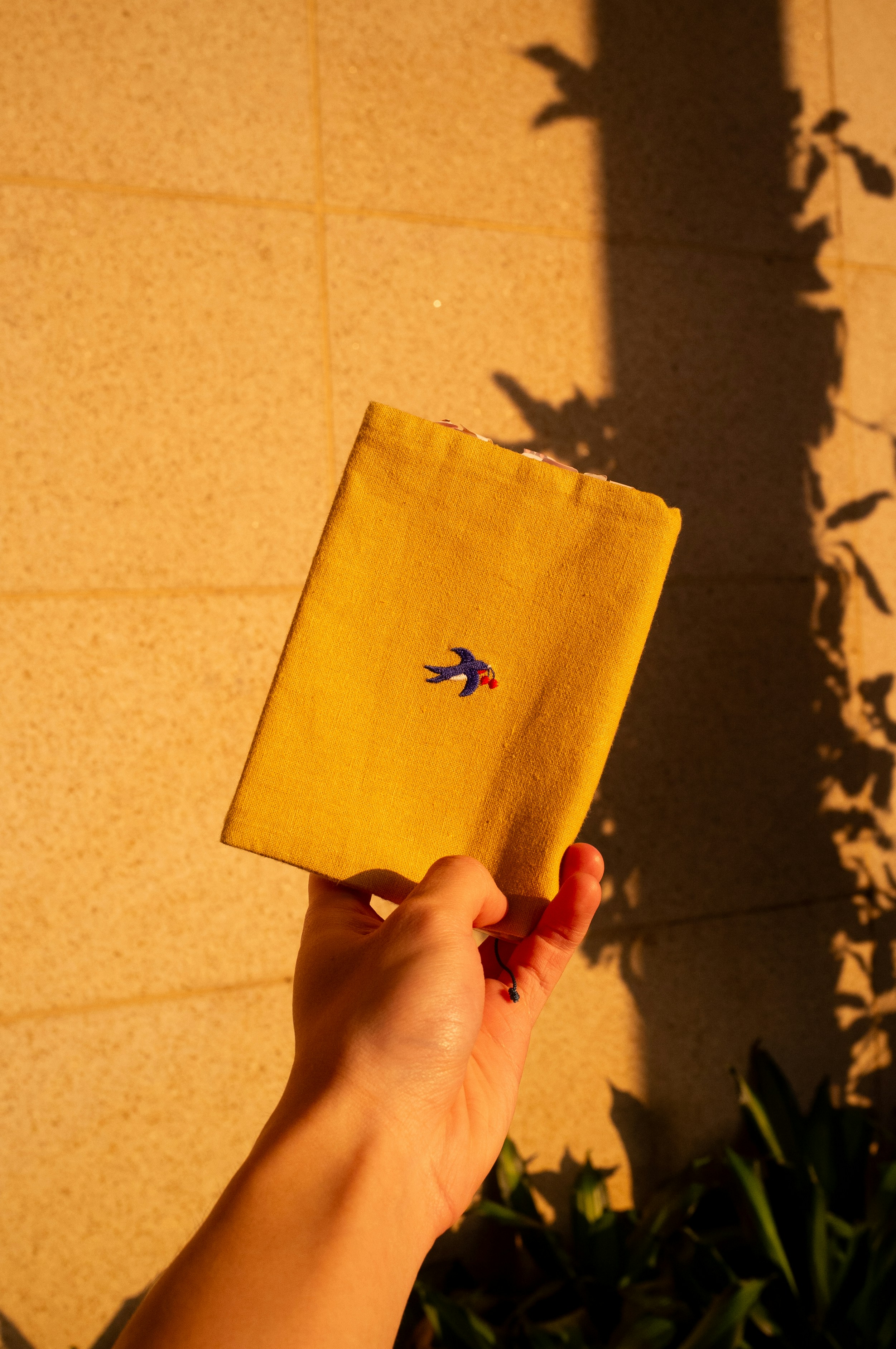 Sunlit Hand-Held Yellow Cloth with a Tiny Bird Emblem