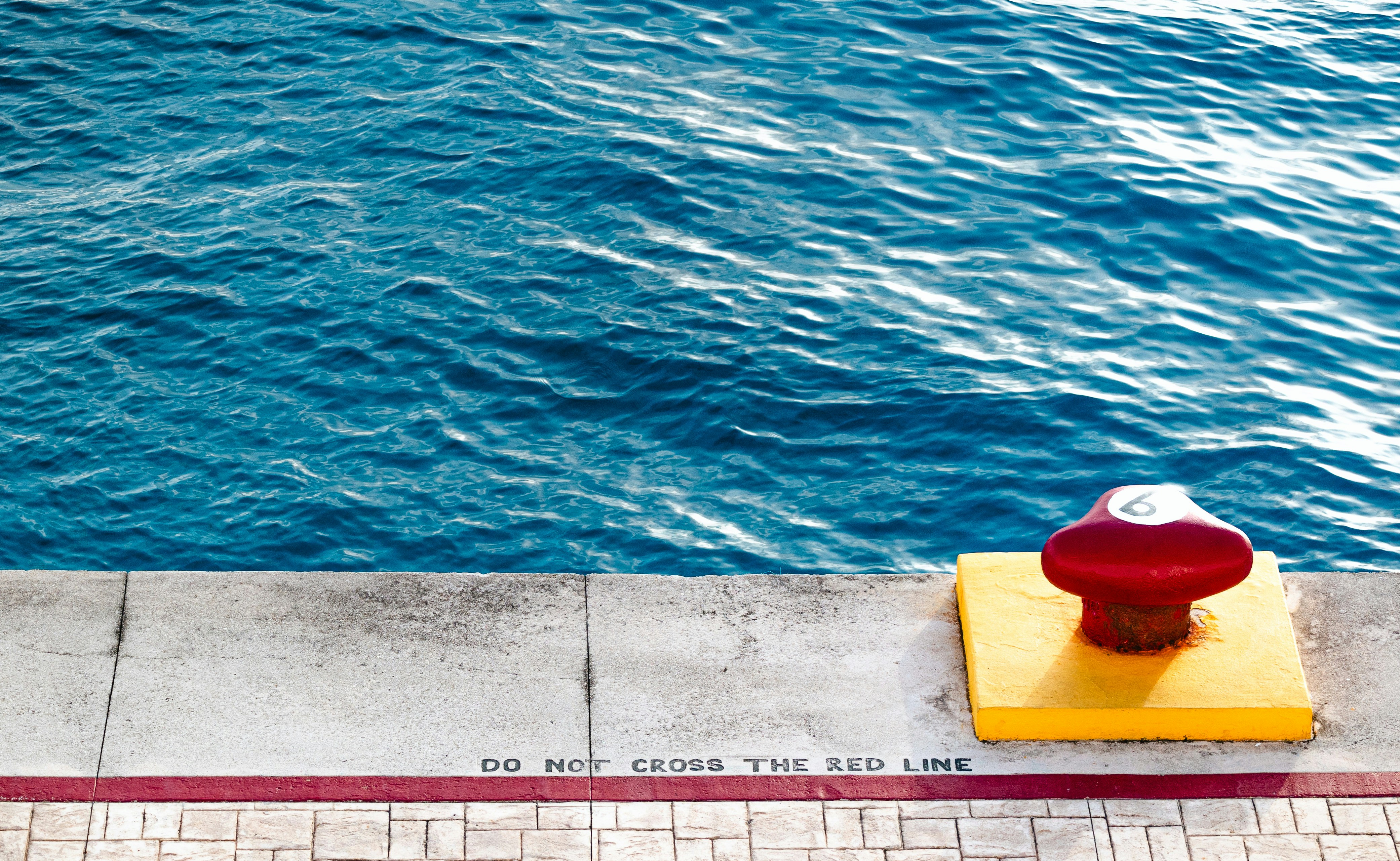 Red Bollard on a Yellow Pedestal Guarding the Harbor Edge
