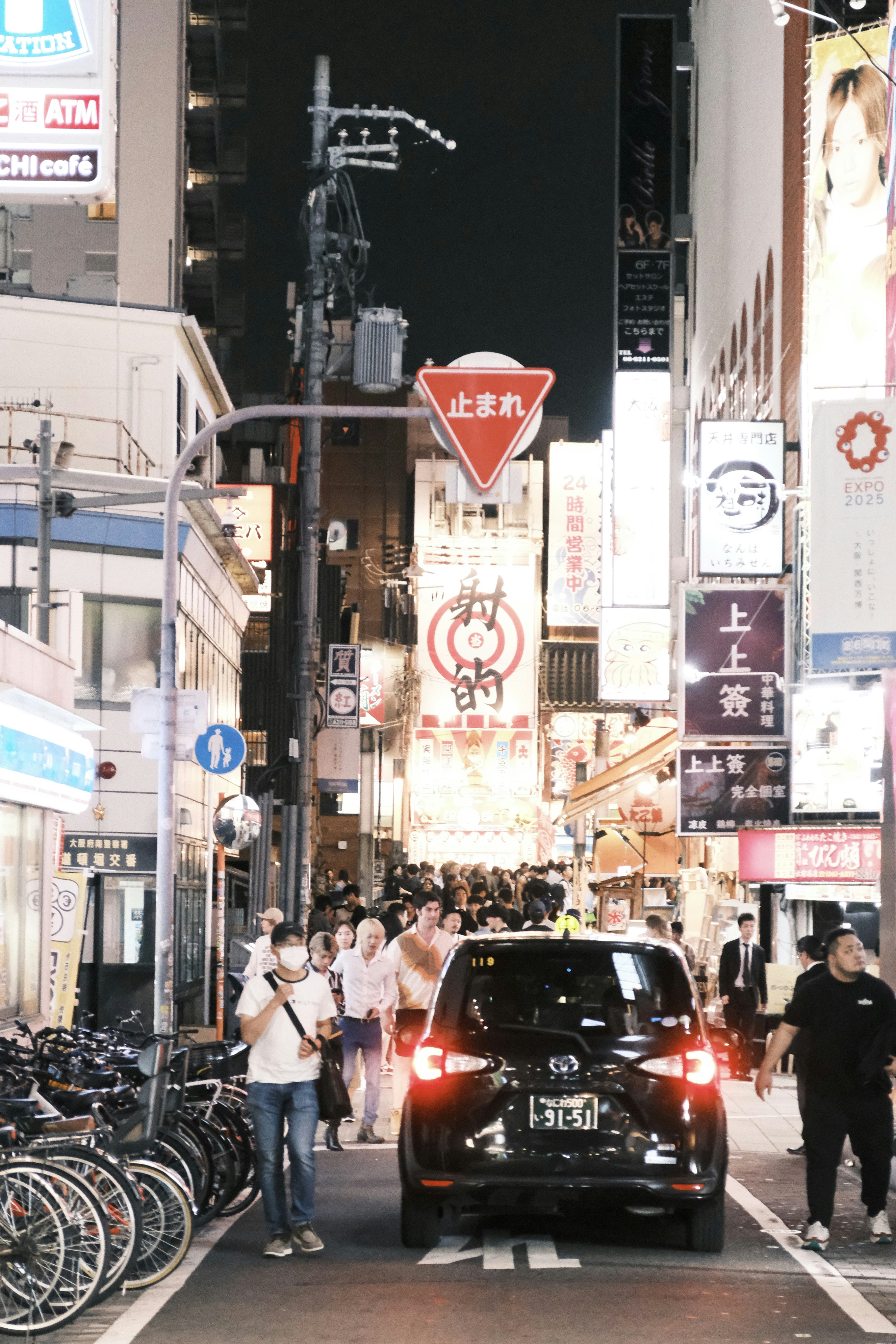 Neon Crossroads: Pedestrians, Bicycles, and a Car in Tokyo’s Night Street Glow