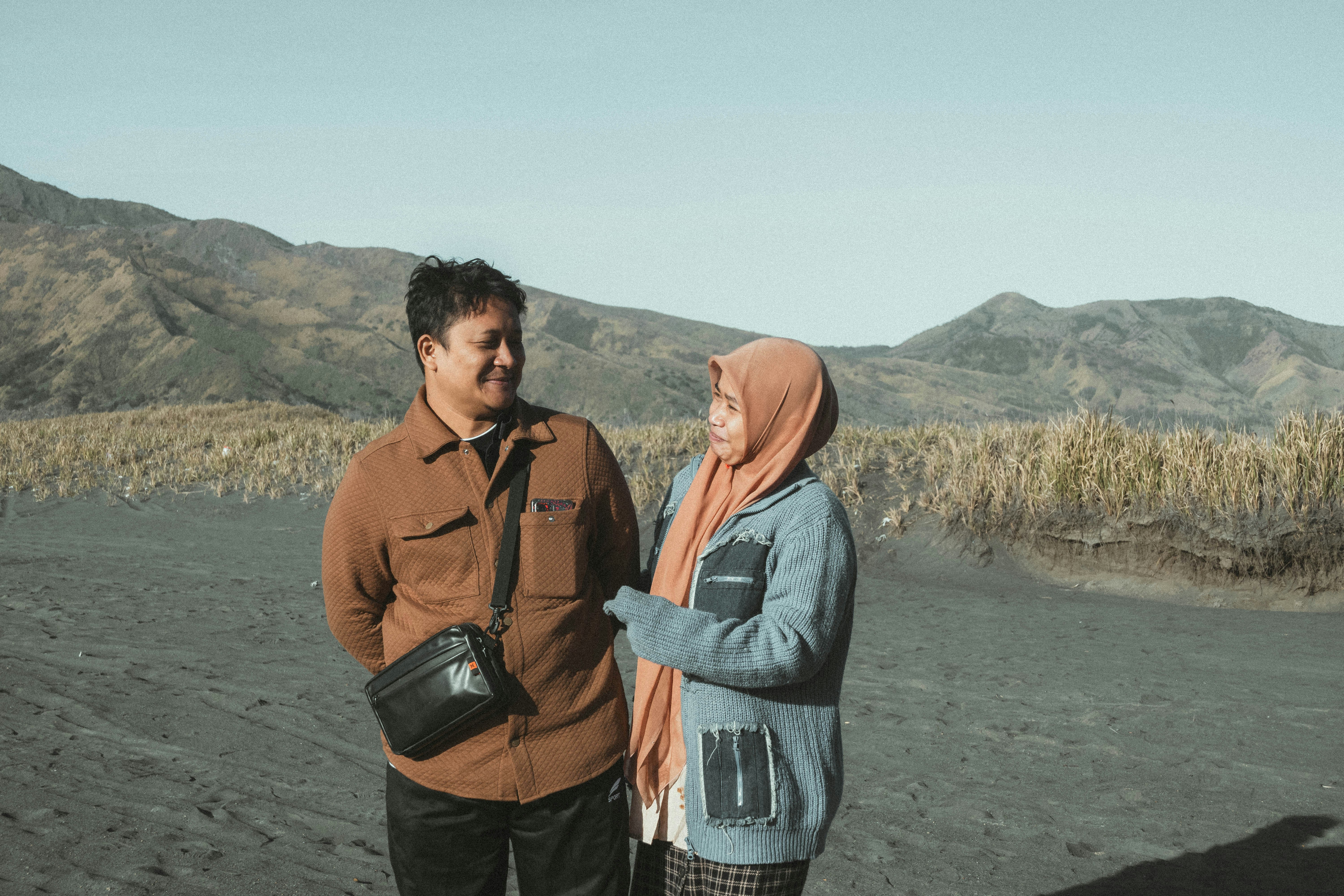 Quiet Exchange on a Windswept Dune Against a Mountain Backdrop