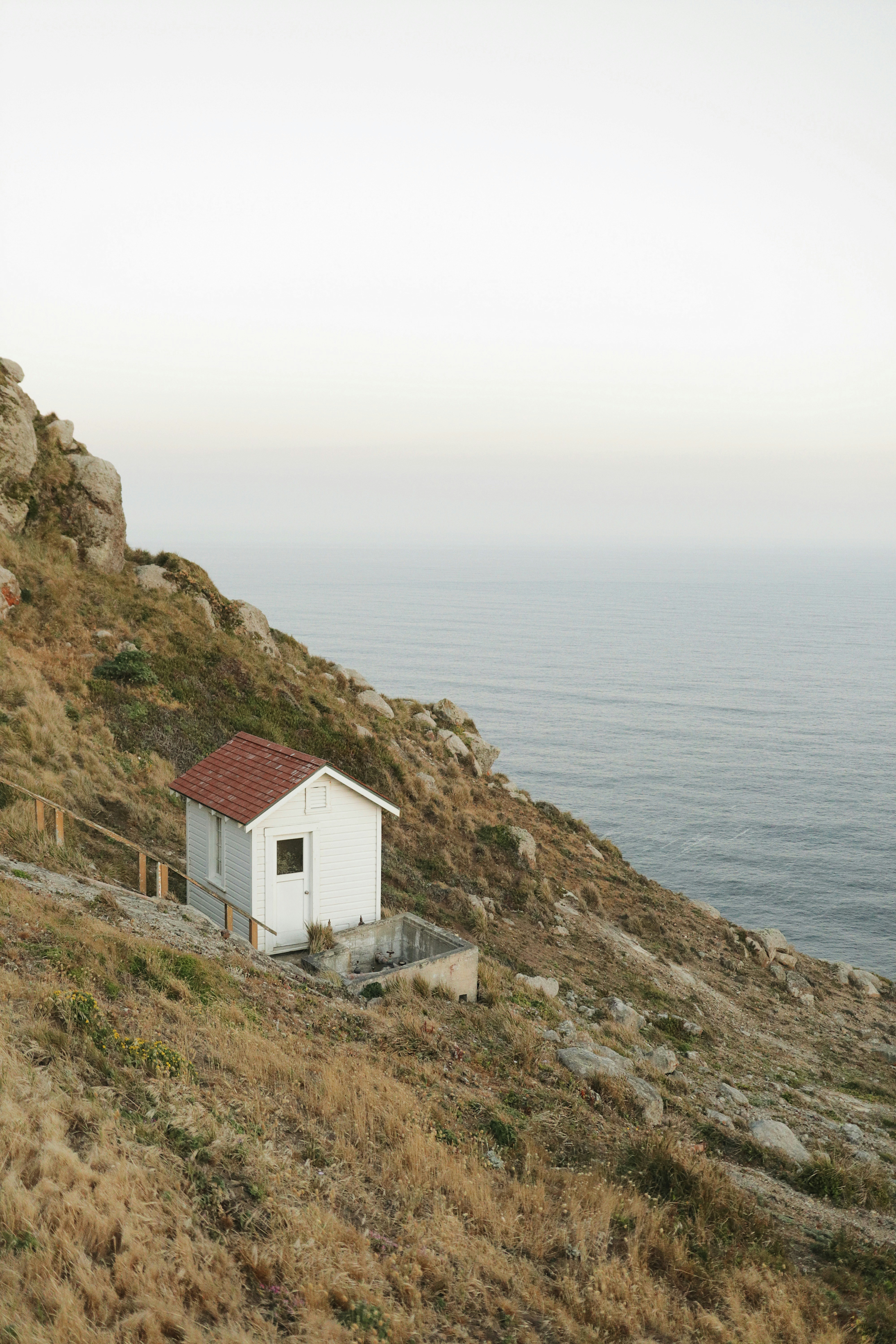 Clifftop Refuge: a white cabin with a red roof overlooking the sea