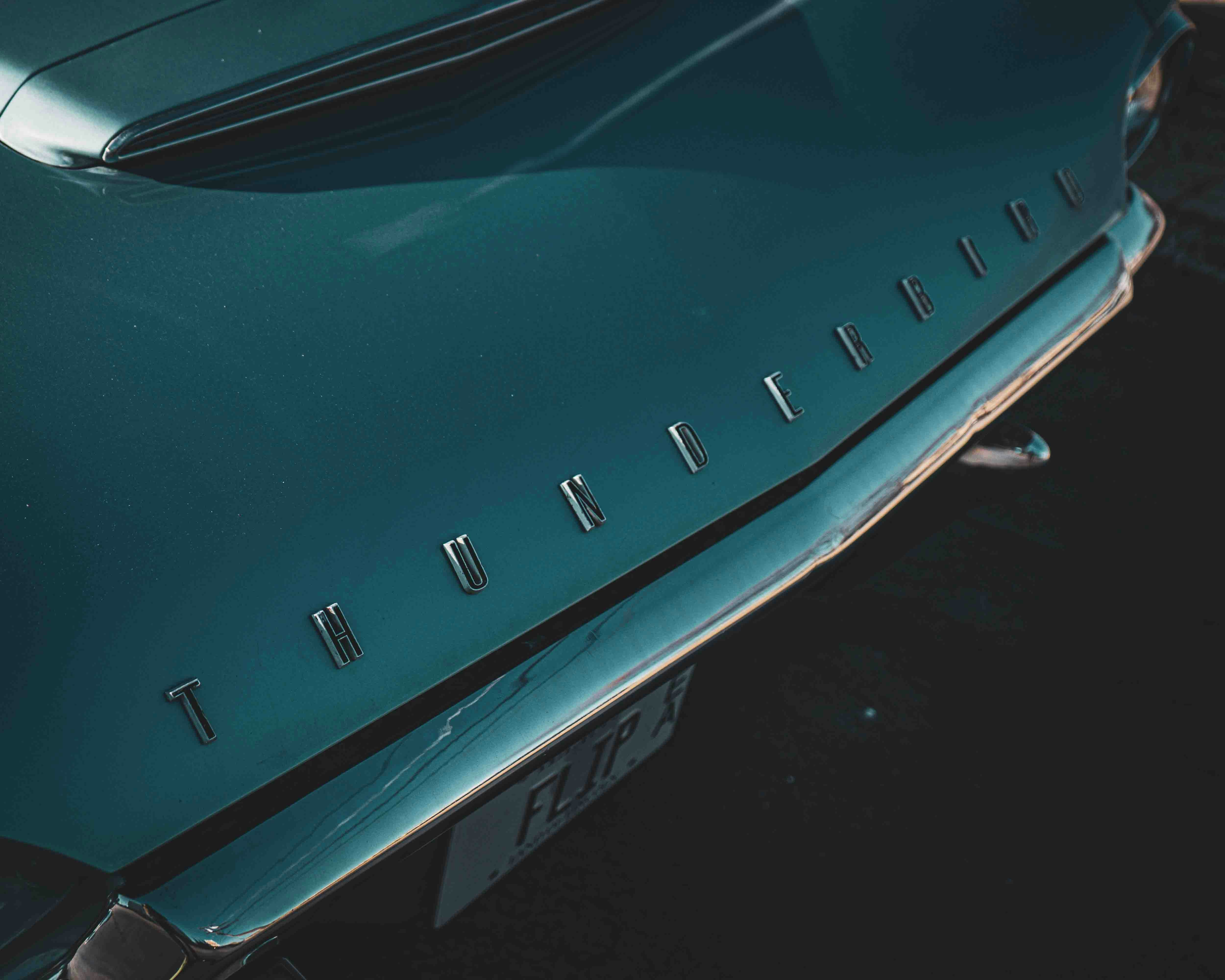 Teal Thunderbird Emblem: Chrome Letters and Curves in Focus