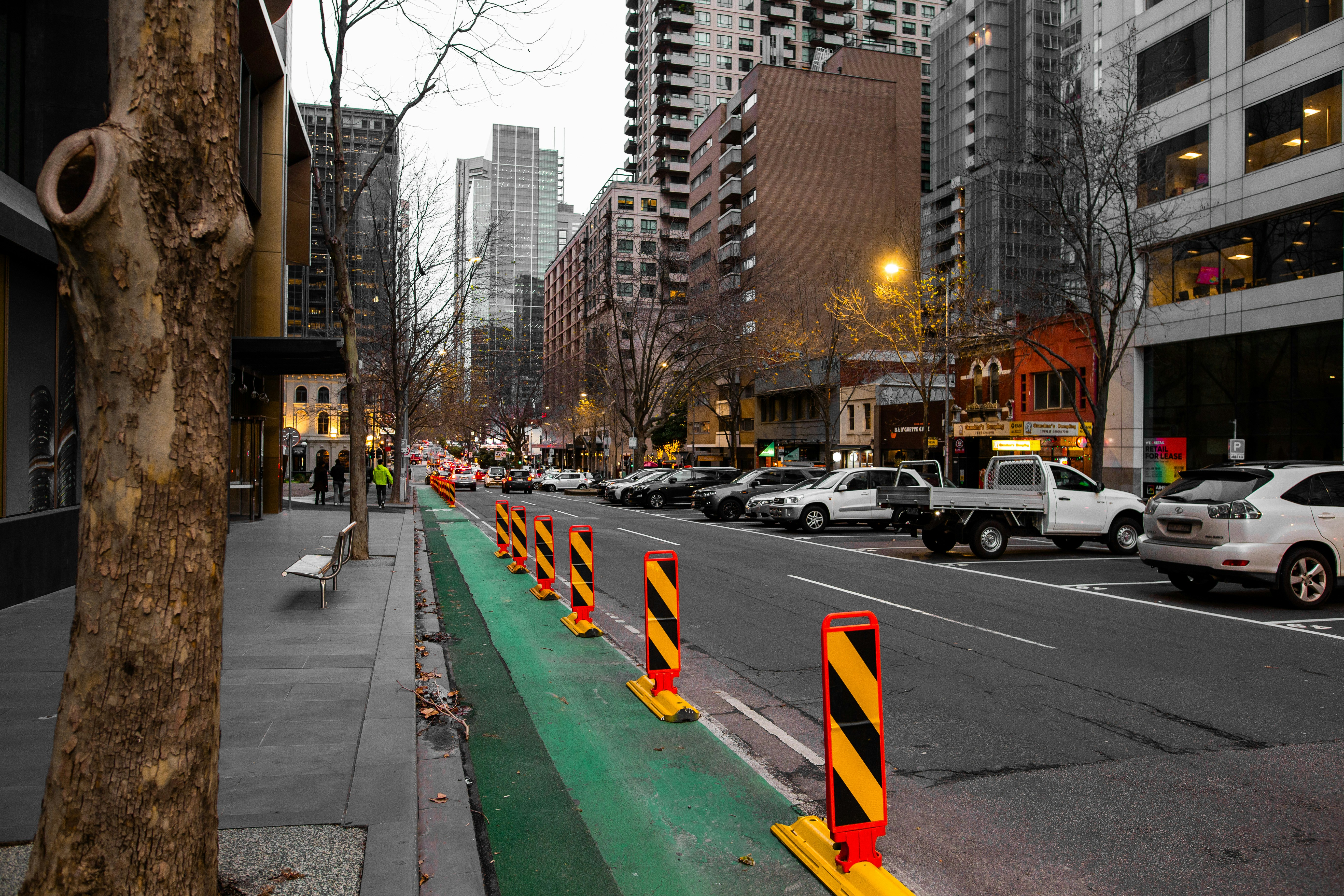 Colorful traffic barriers line a newly designated bike lane in a bustling city street, showcasing urban development and infrastructure improvements.