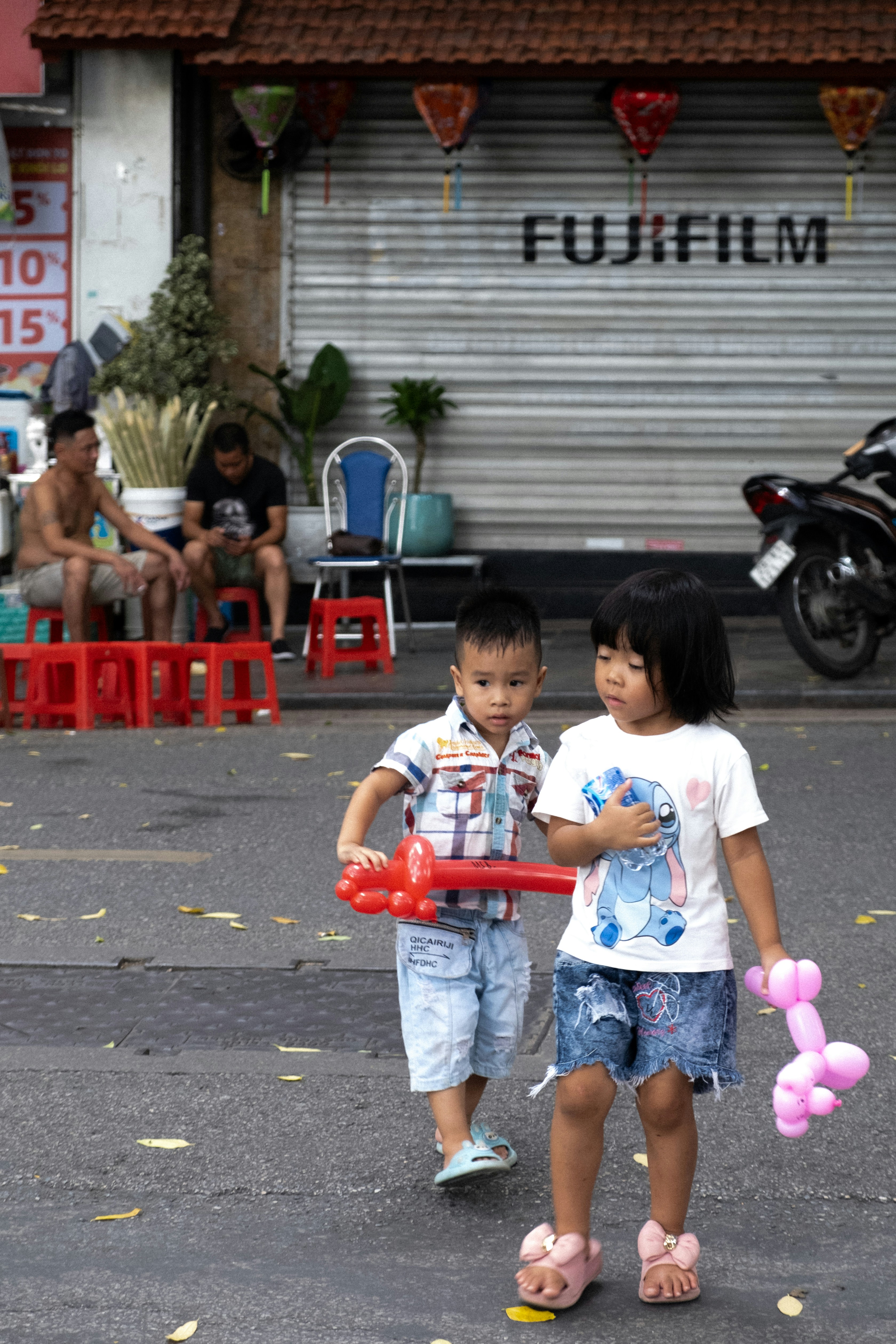 Balloon Buddies on a Quiet Street in Front of a Closed Fujifilm Shopfront