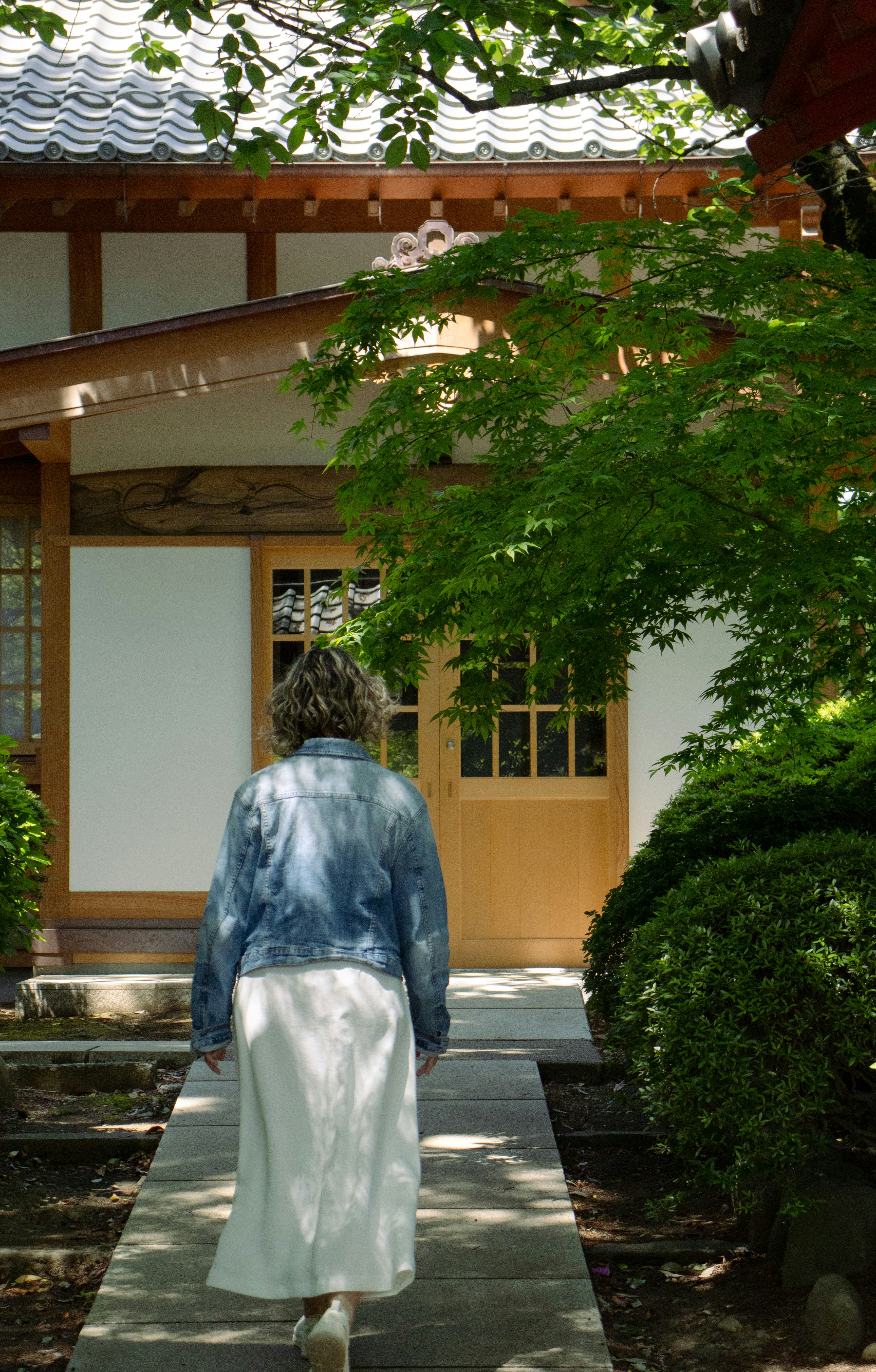 Denim-Clad Wanderer Approaches a Warm Wooden Door in a Japanese Courtyard