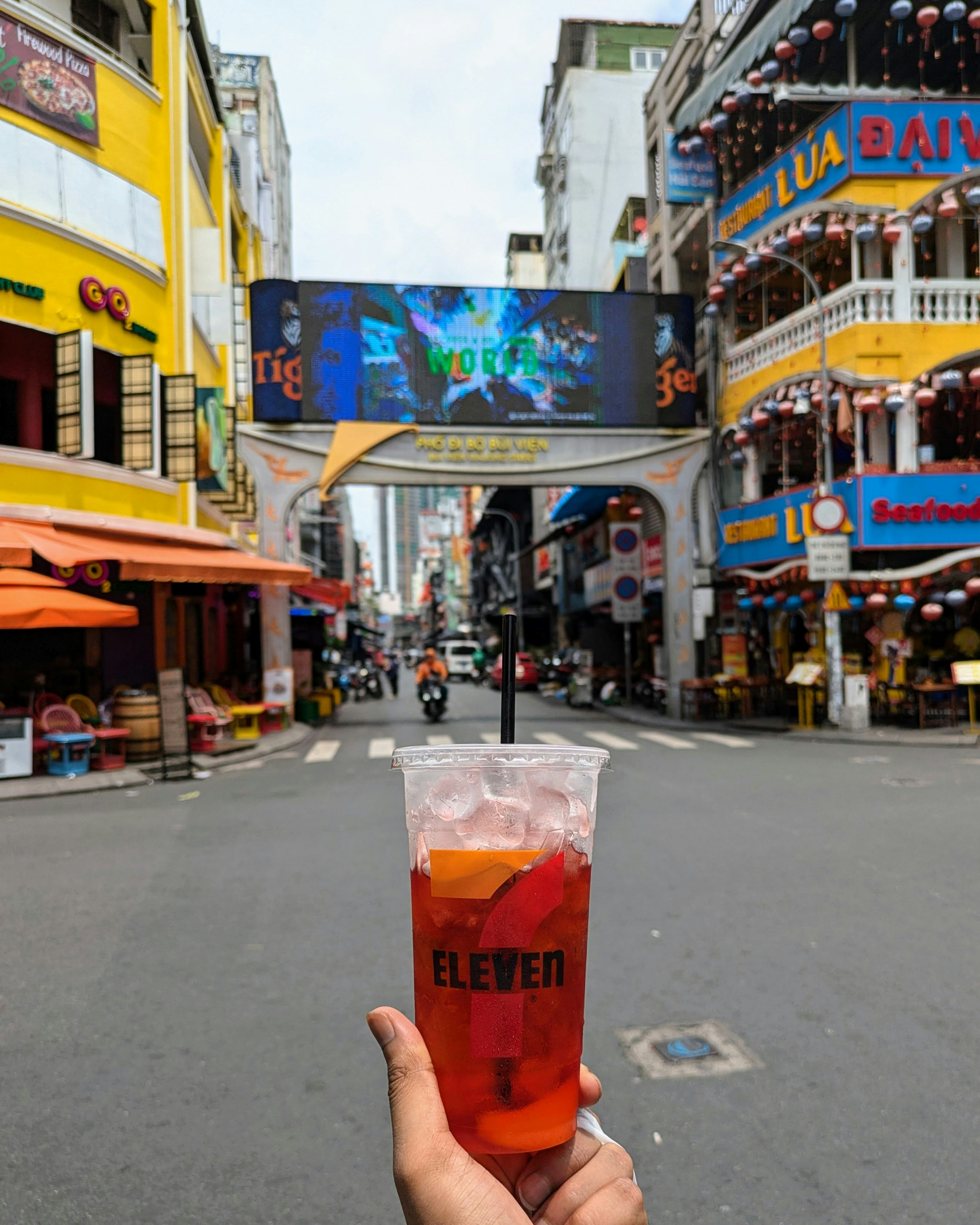 A person holding up a drink in the middle of a street photo – Free Ho ...