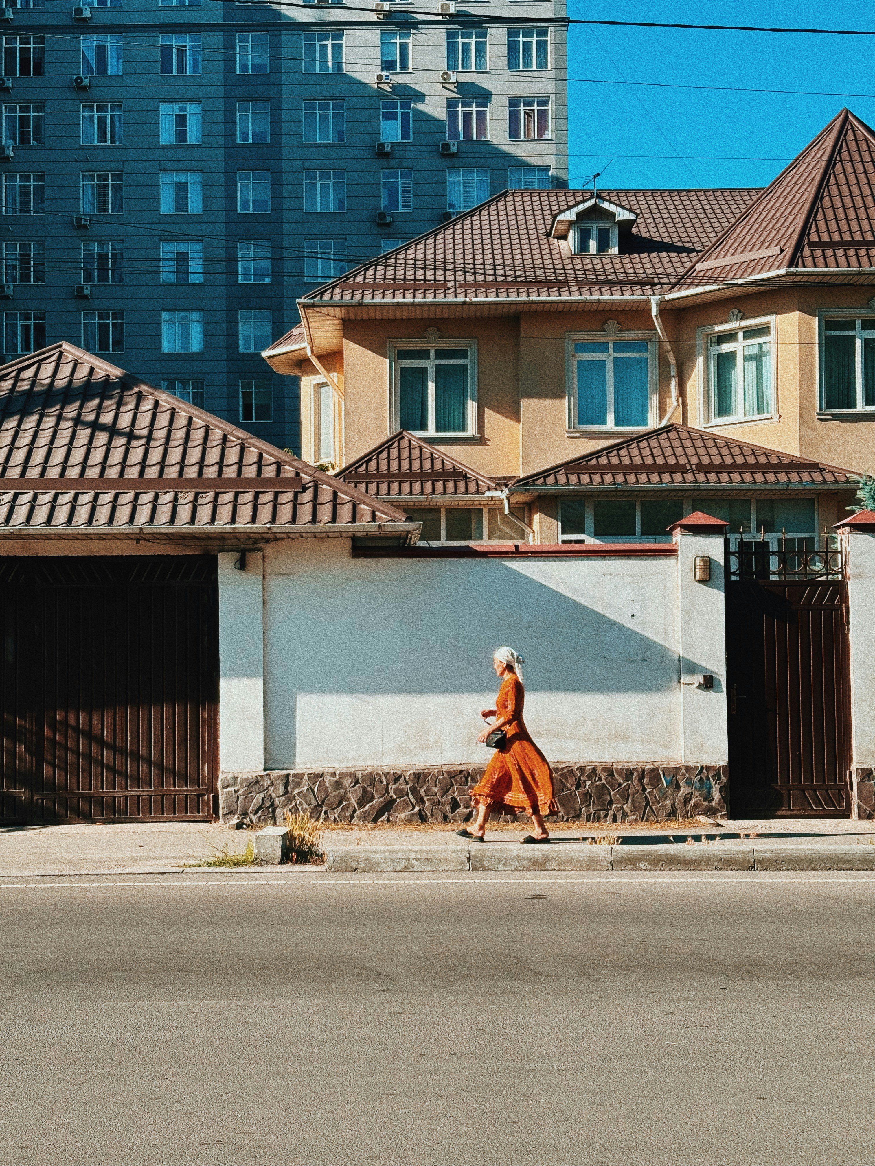 Orange on a Quiet Street: A Moment Between Brick Townhouses and a Blue Tower