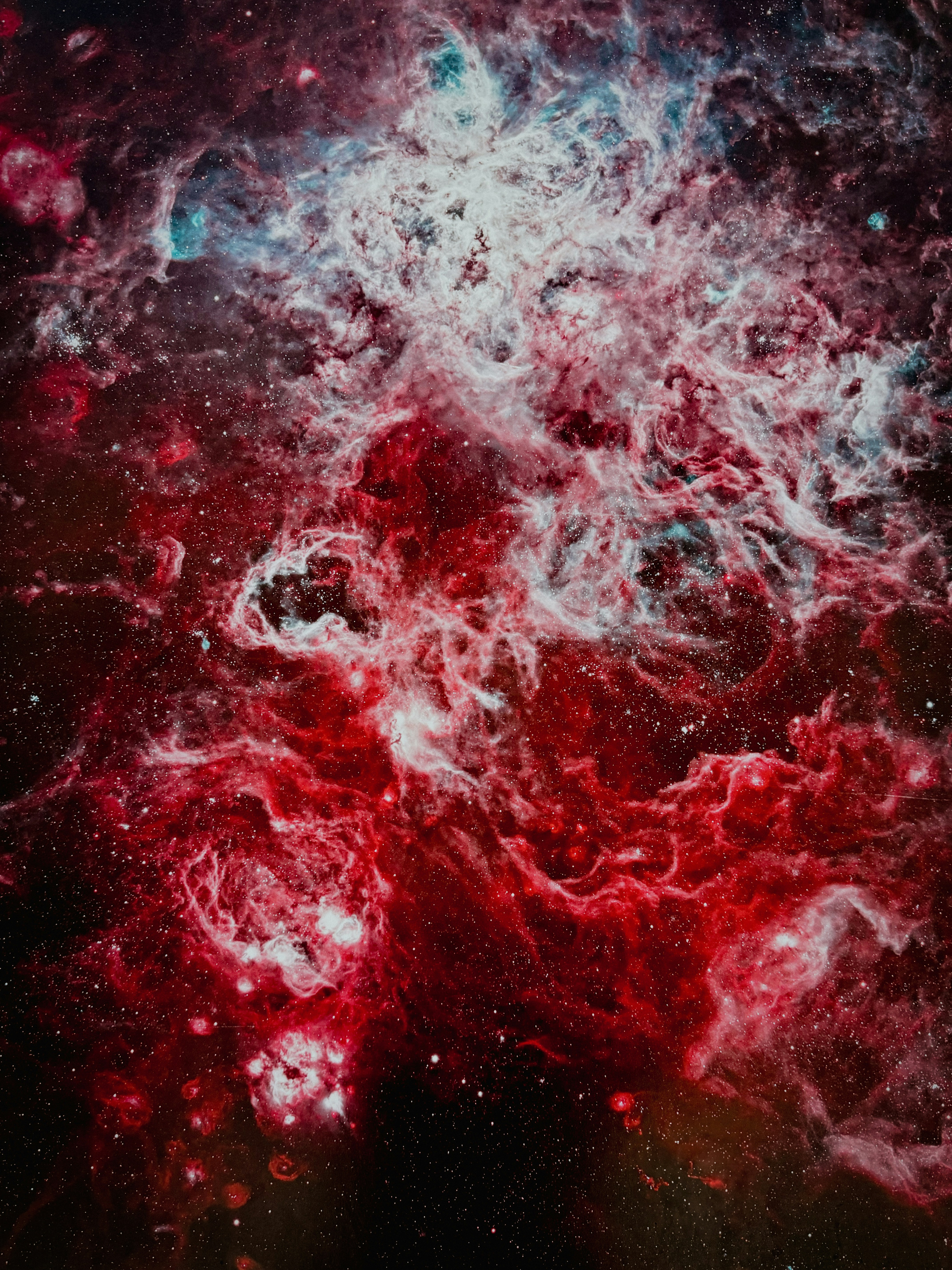 Astronomical photograph of a red nebula with white filaments and a starry field.