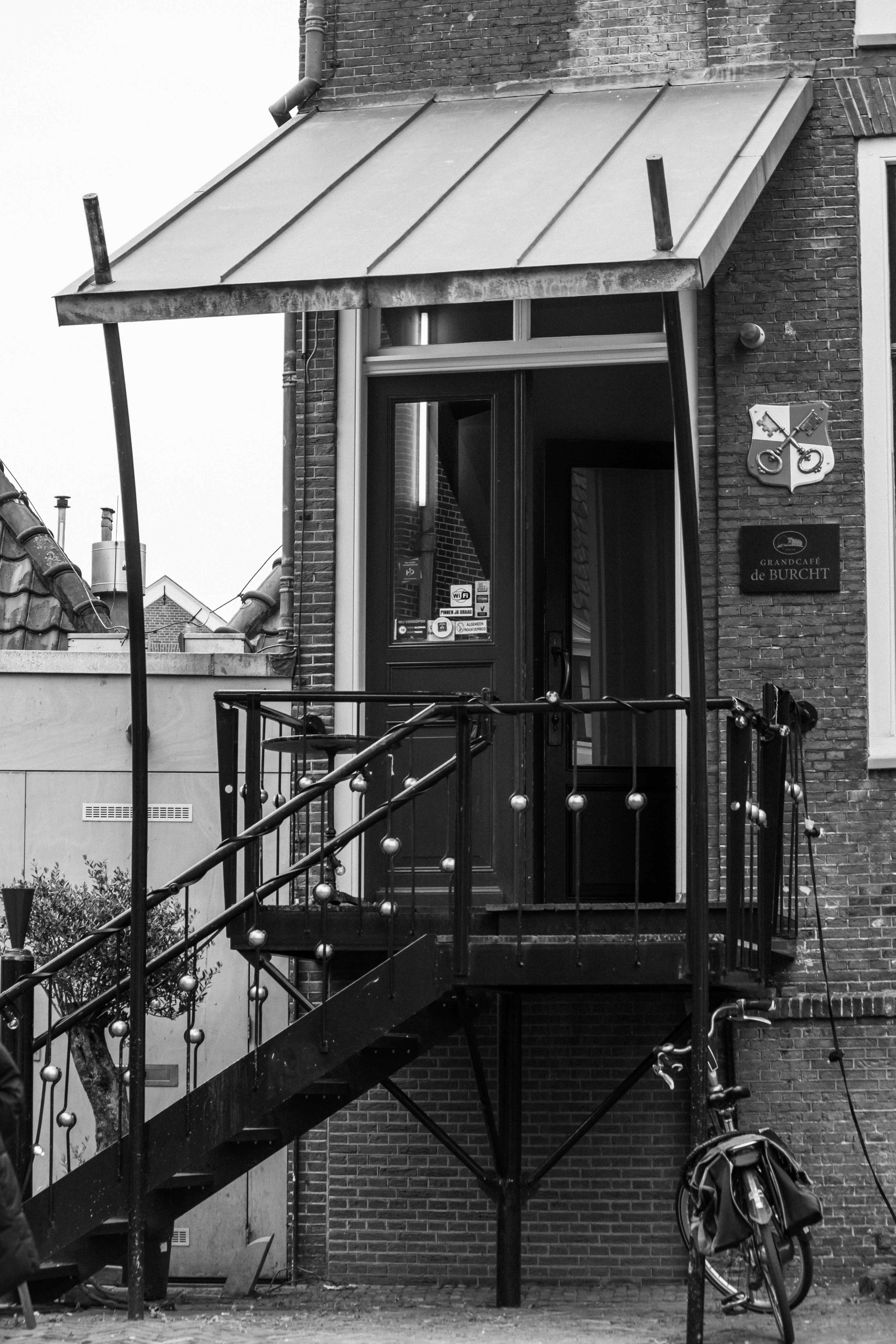 Black and white image of a stairway leading to a doorway with a bicycle parked nearby.
