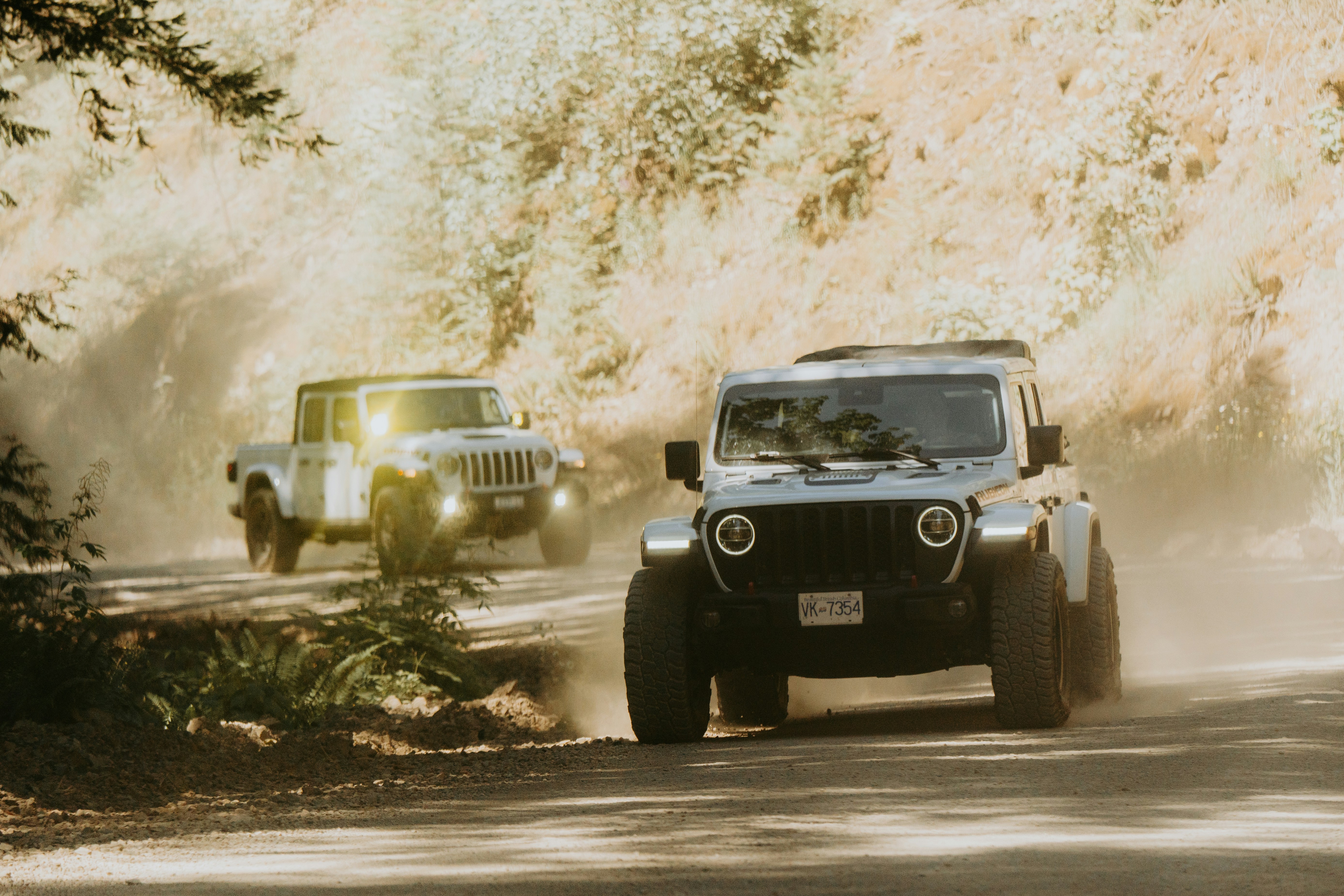 A couple of jeeps driving down a dirt road photo – Free Machine Image ...