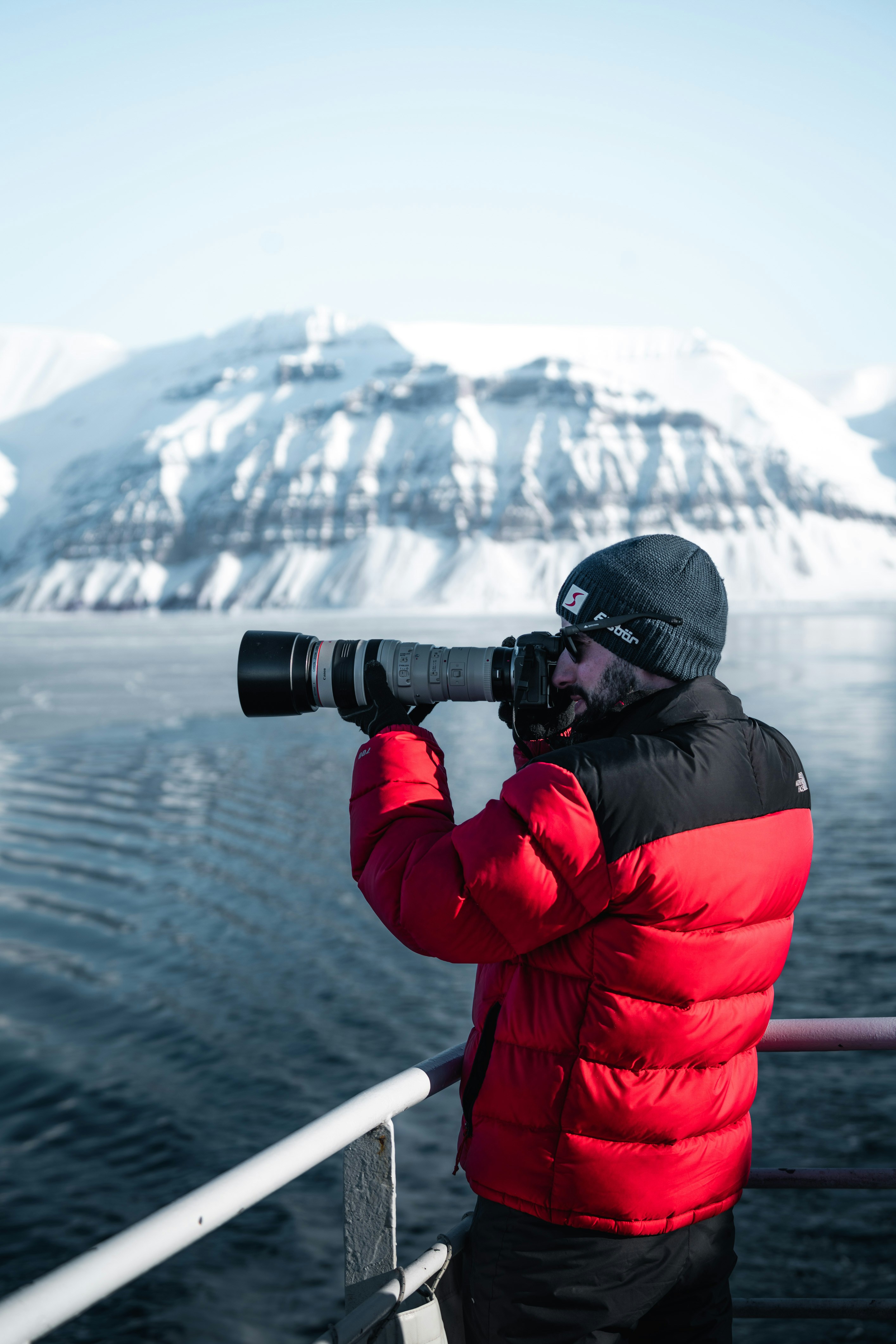 Telephoto Arctic Portrait: A Red-Jacket Photographer Against a Glacier Backdrop