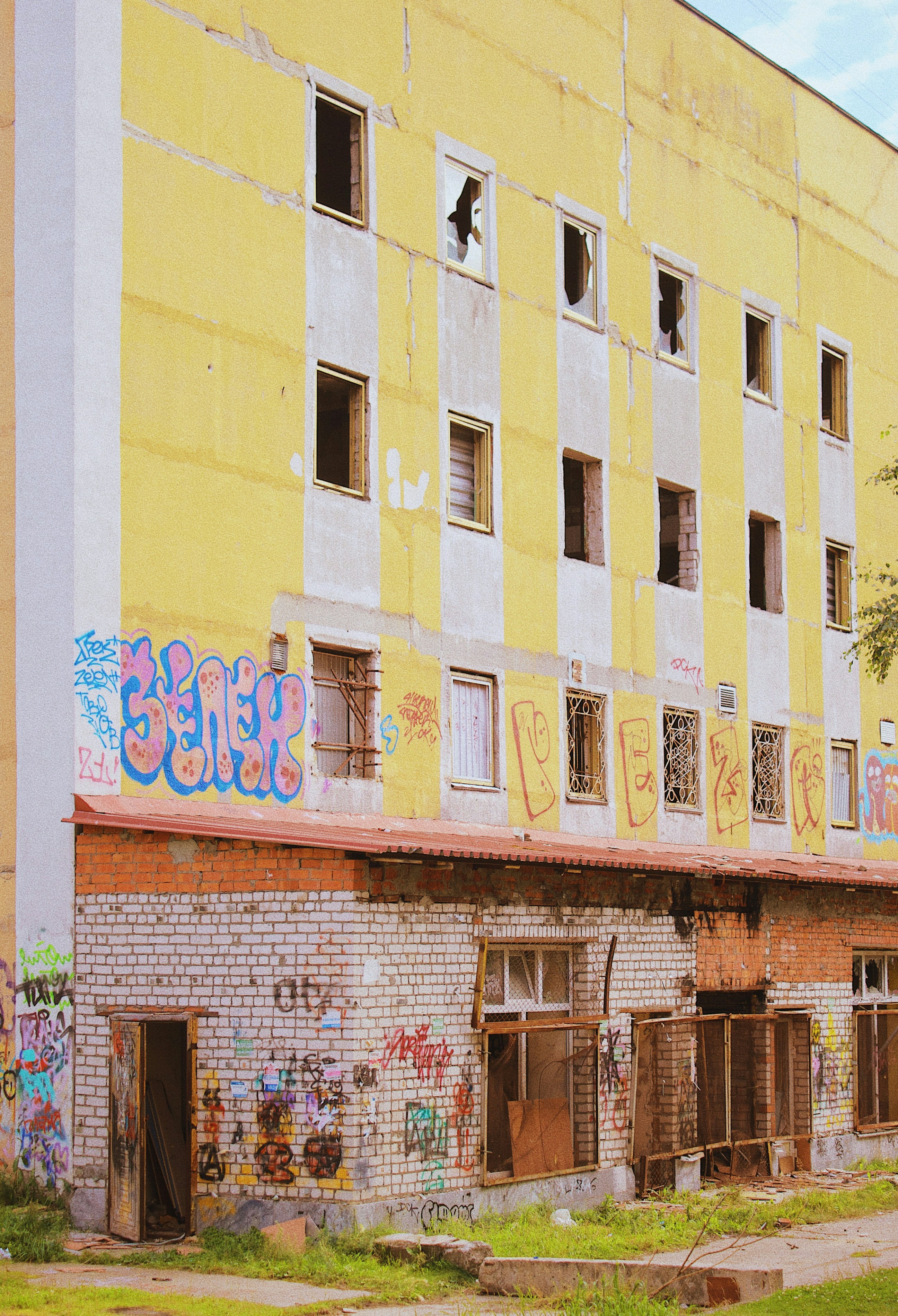 Graffiti-Filled Facade Rising Above a Bricked Annex