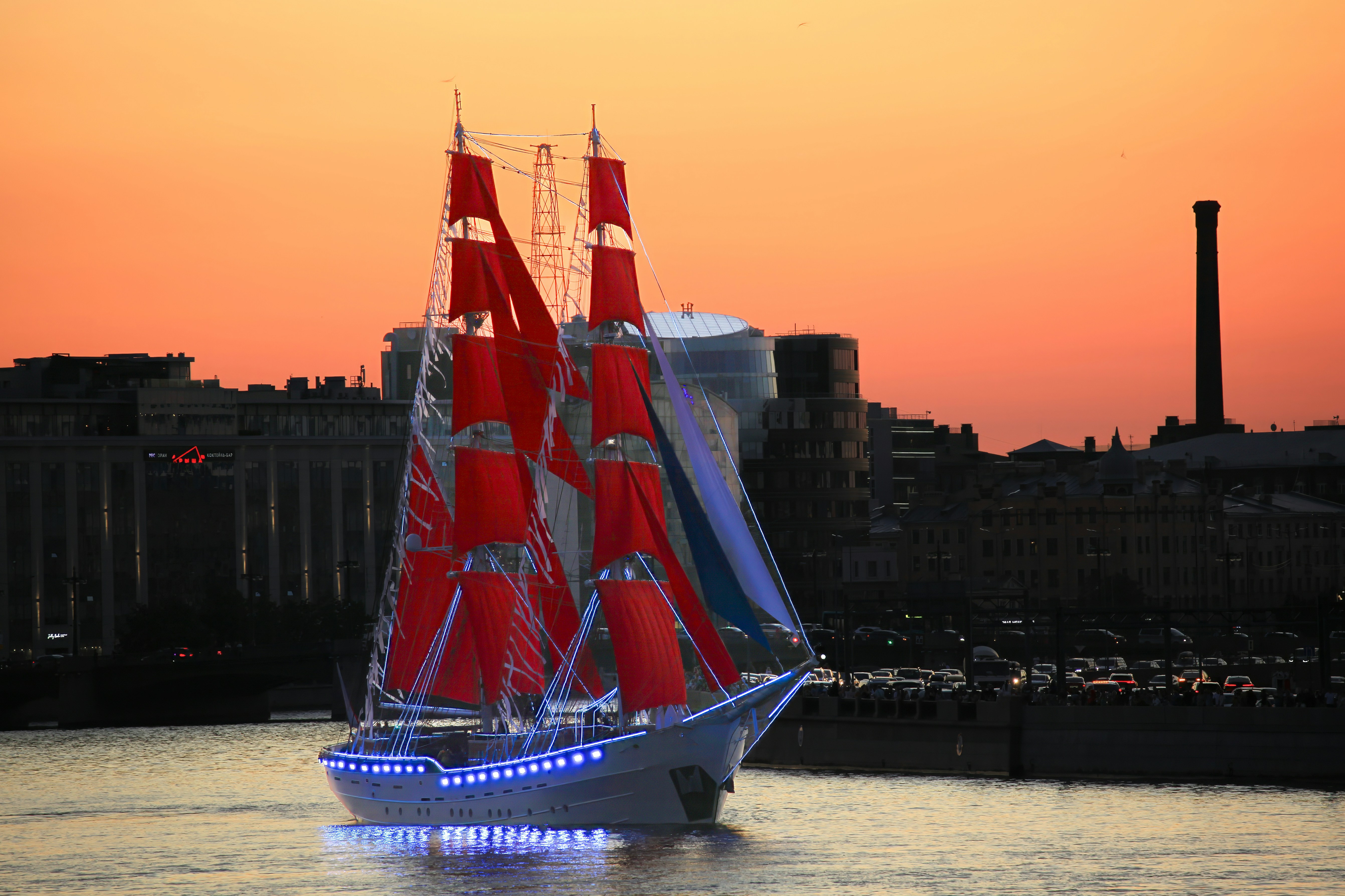 Crimson Sails at Dusk: Harbor Lights on a City Horizon