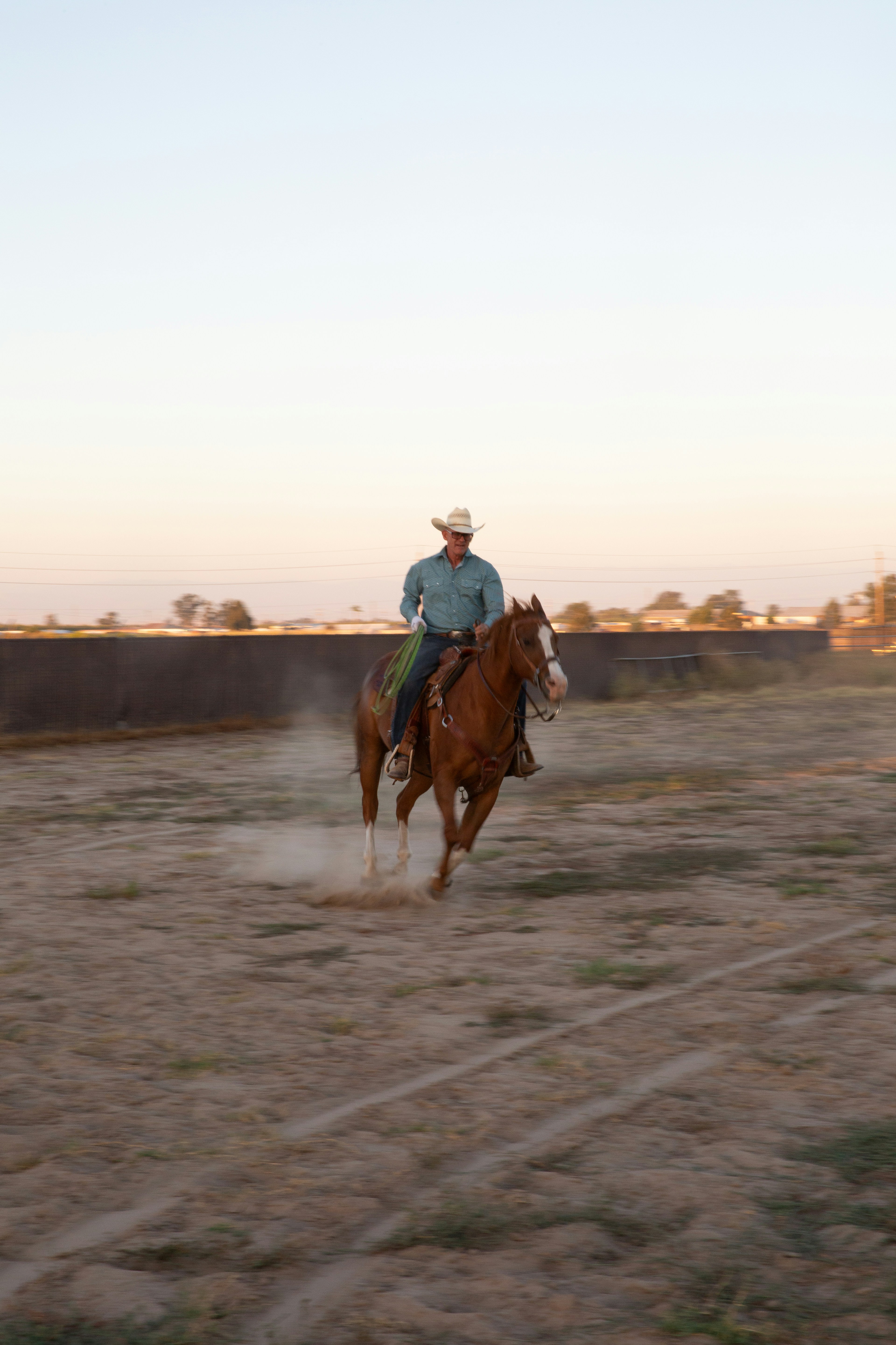 Cowboy riding his brown horse in a field