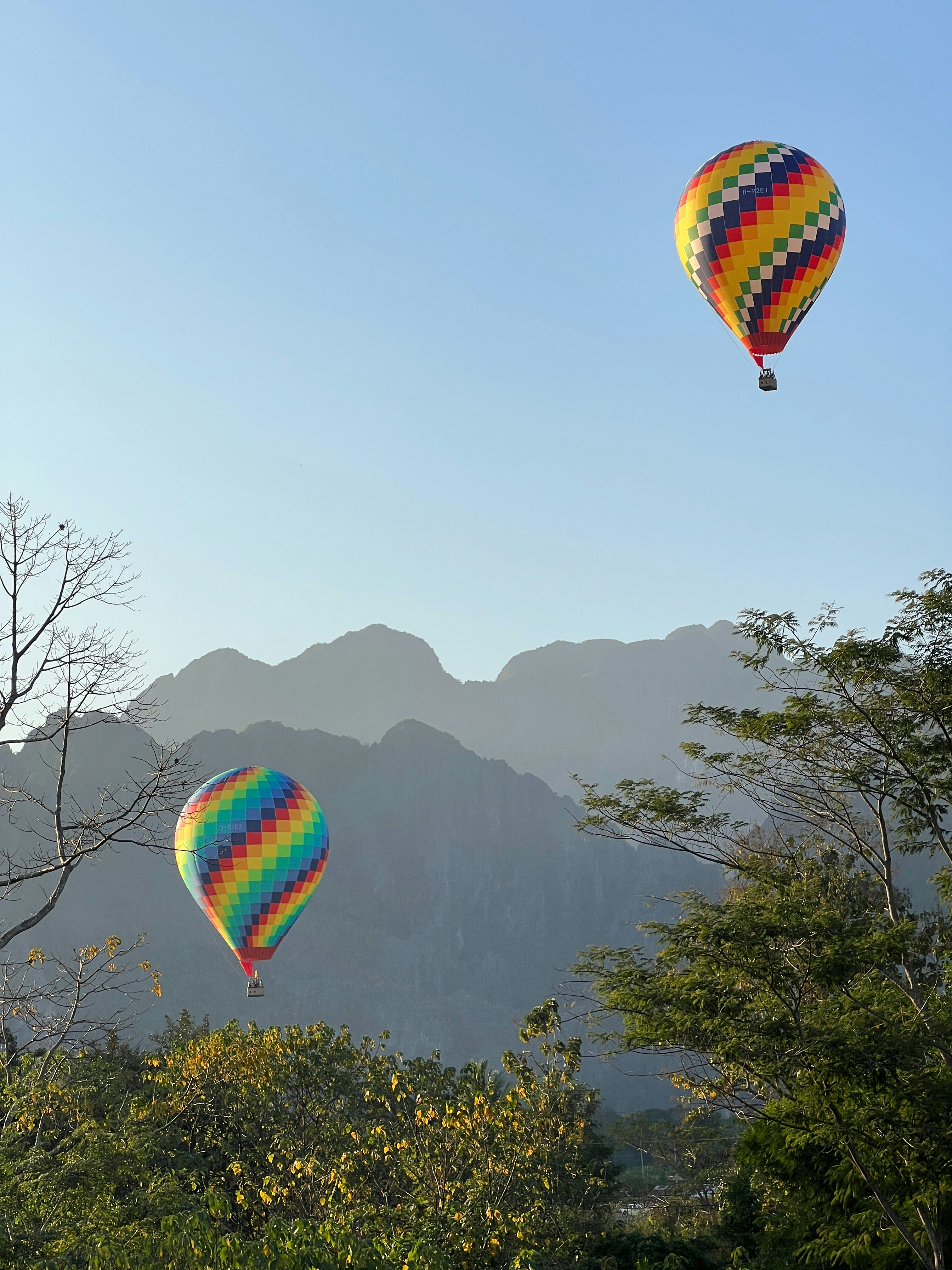Chromatic Balloons Drifting Above a Quiet Mountain Valley