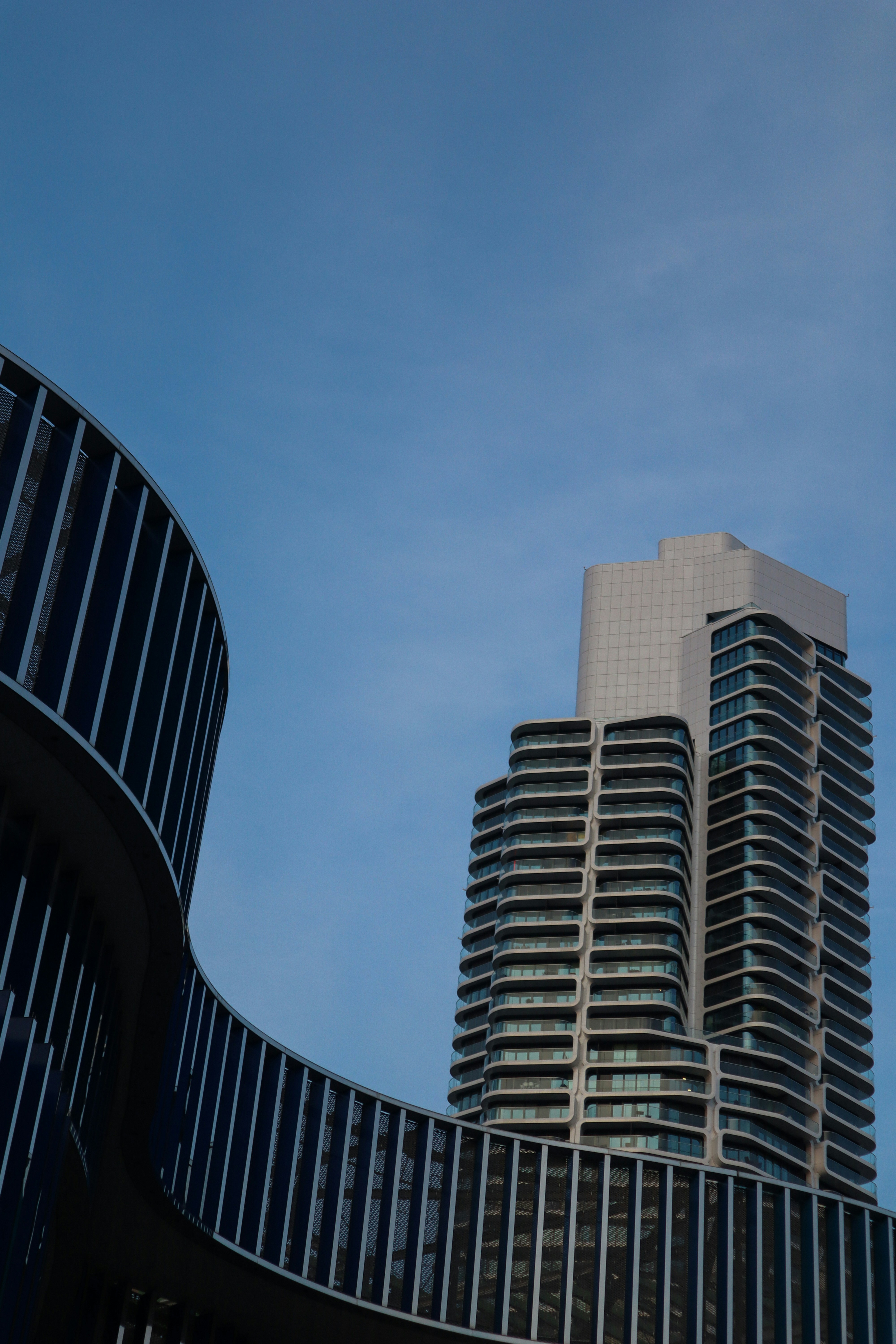 Modern skyscrapers with curved facades rise against a clear blue sky.