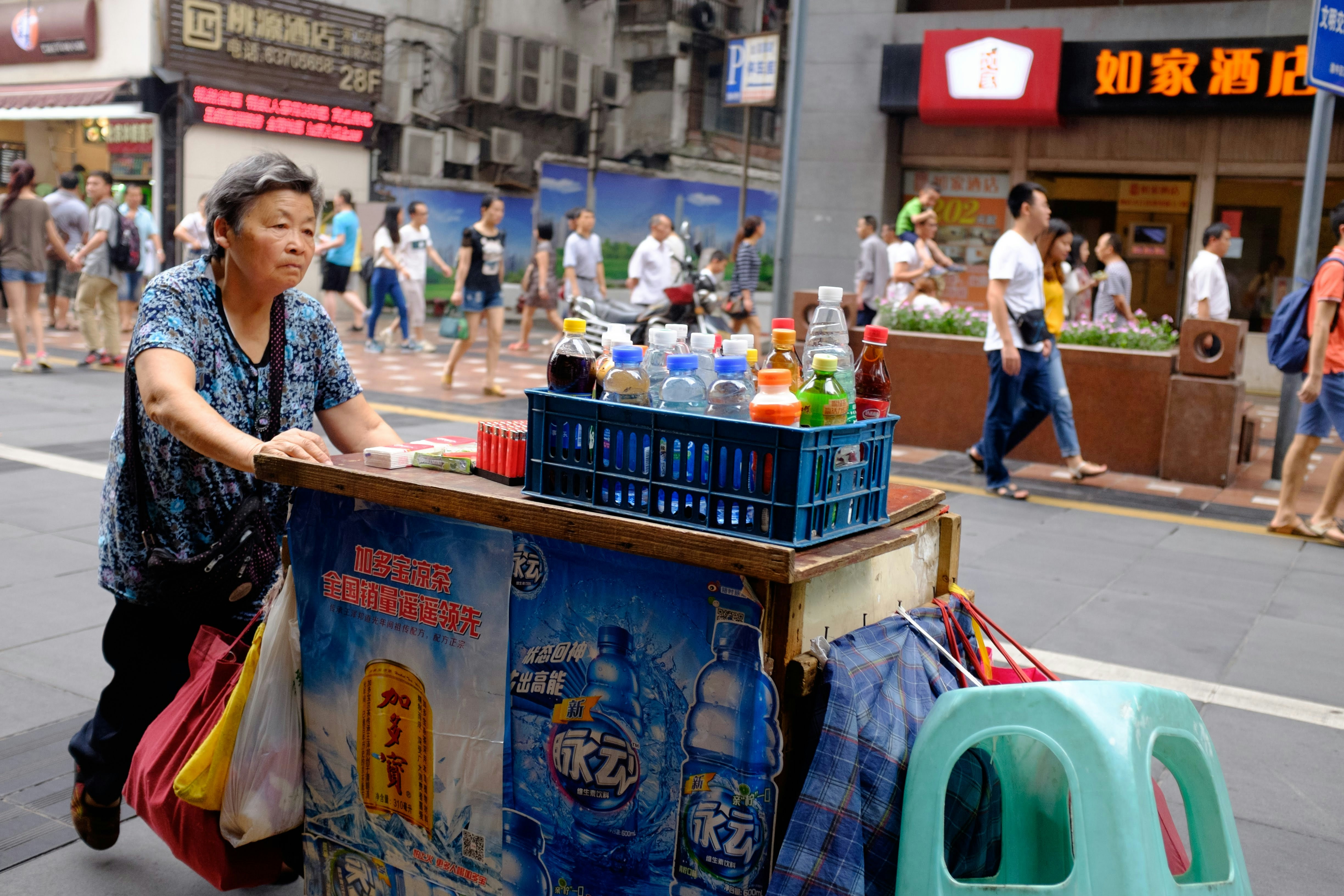 A woman walking down a street past a street vendor photo – Free ...