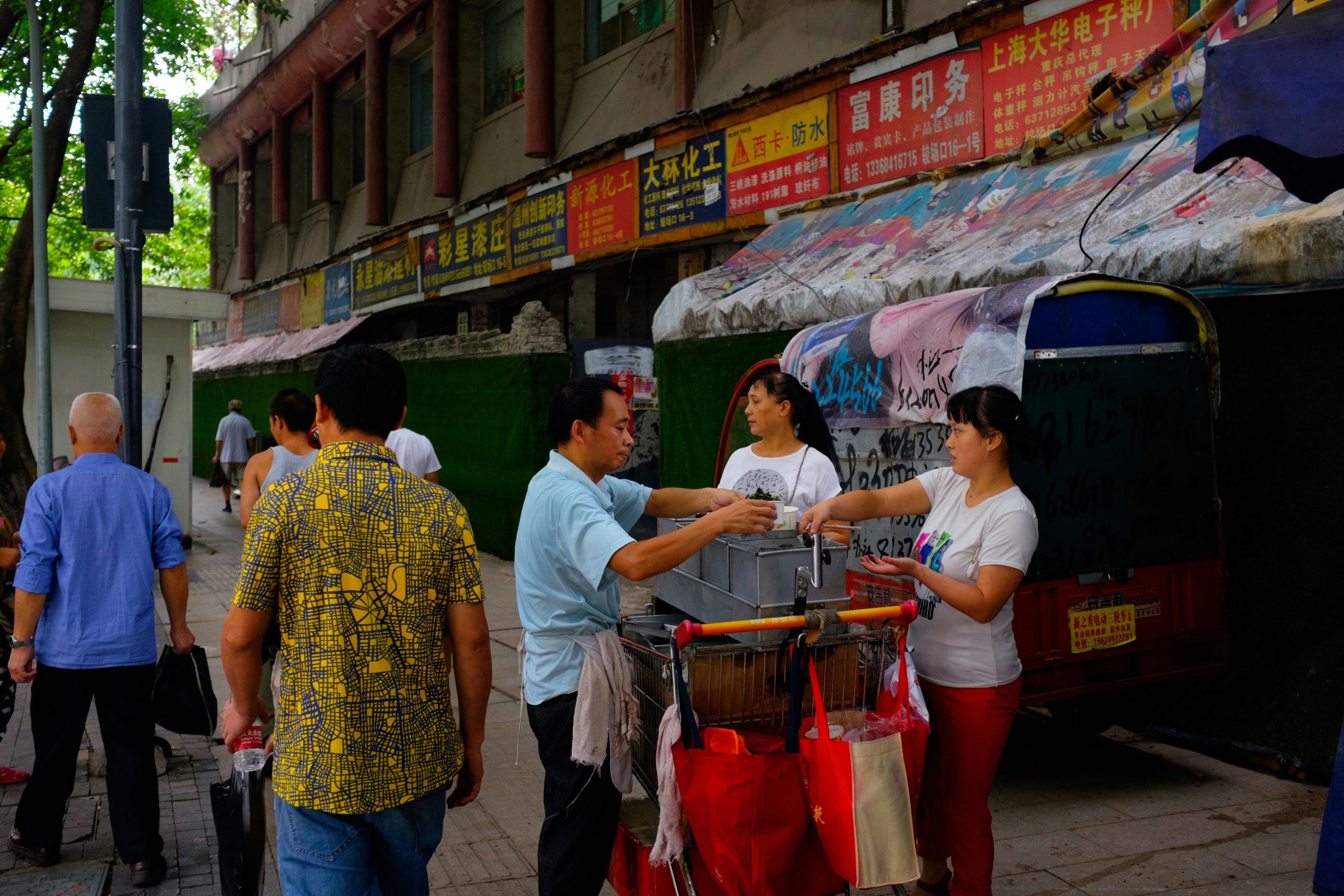 A group of people walking down a street photo – Free Street vendor ...