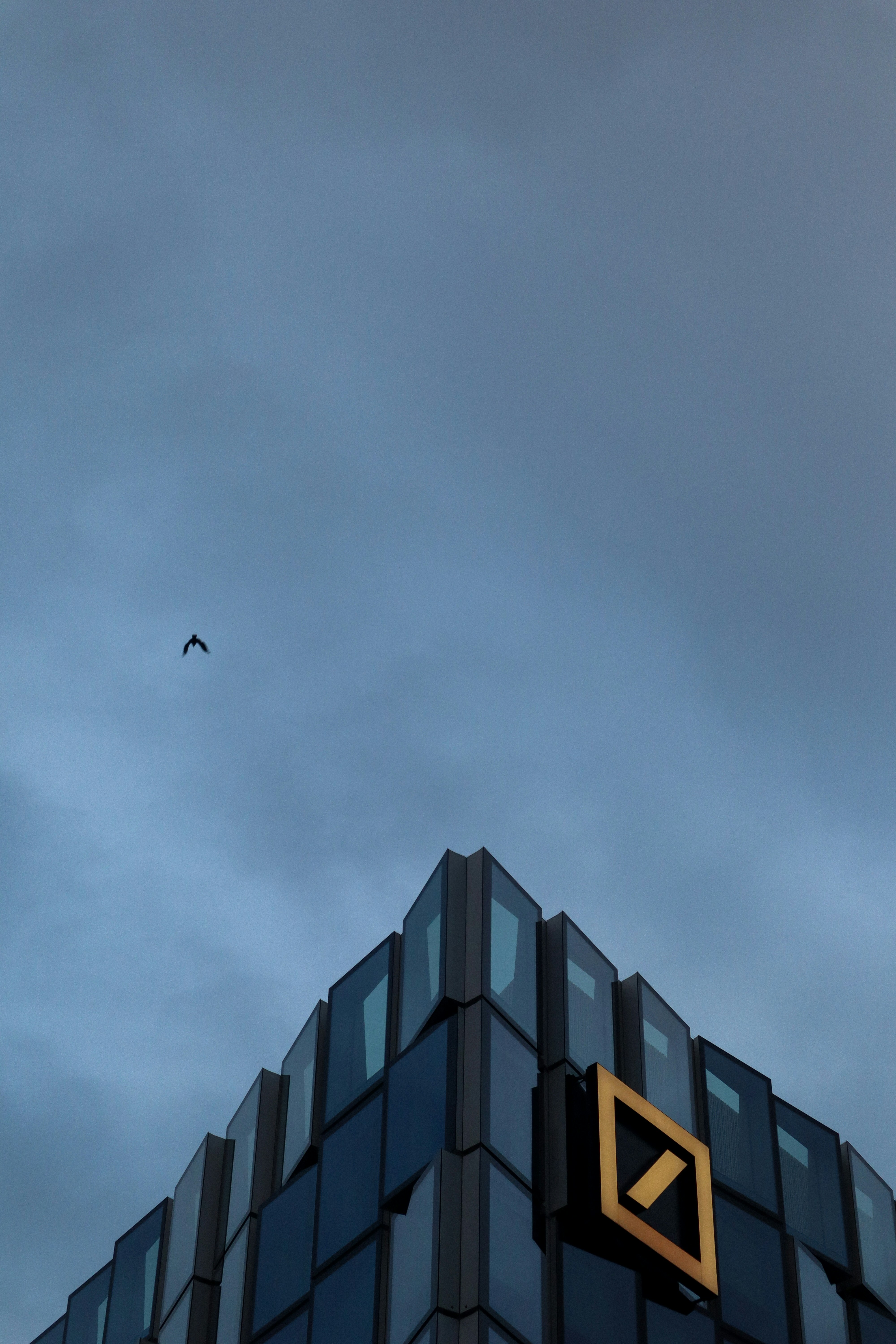 Golden Emblem on a Glass-Tiled Corner Against a Quiet Sky