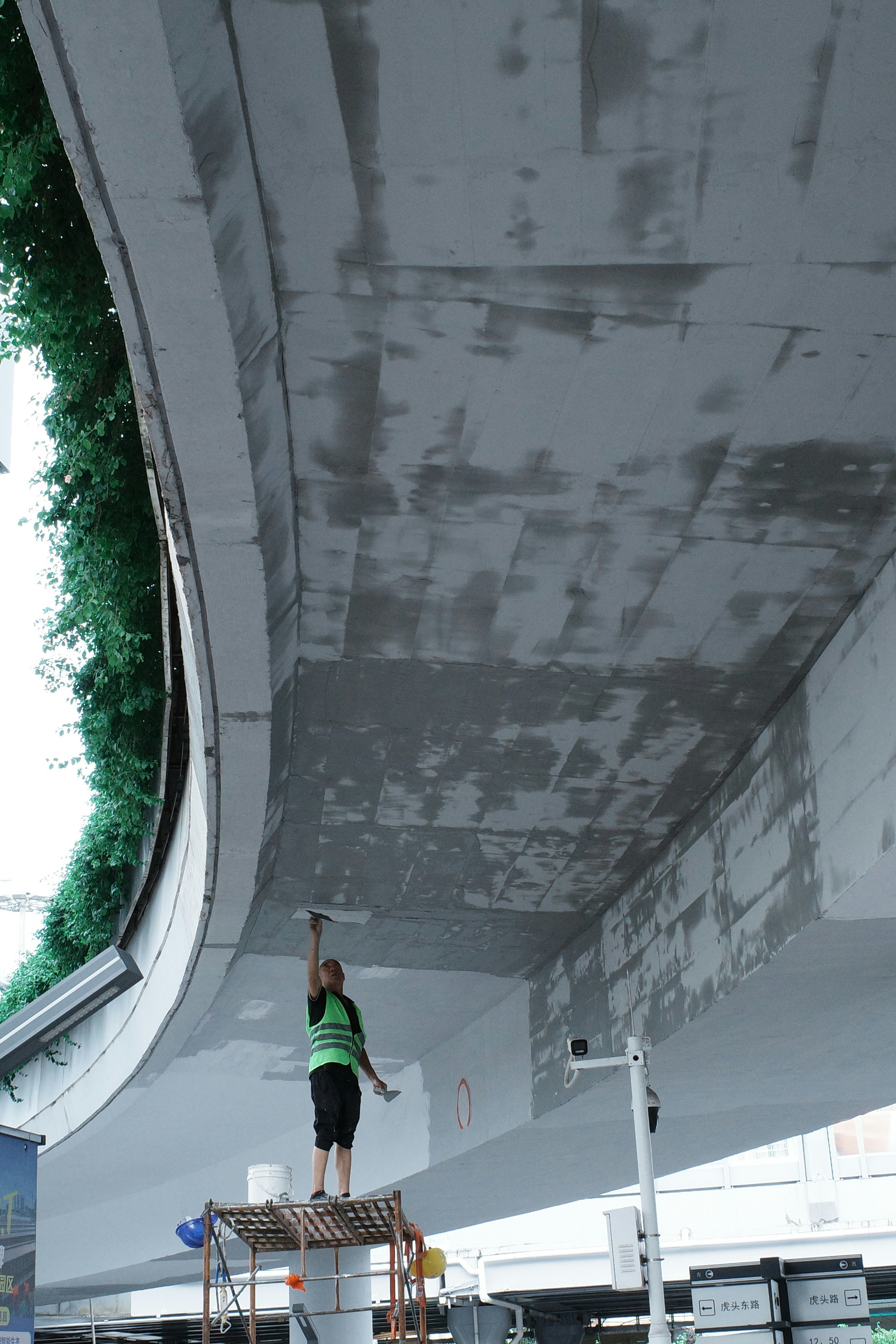 Under the Curve: A Scaffolding Worker Reaches Toward the Concrete Arc