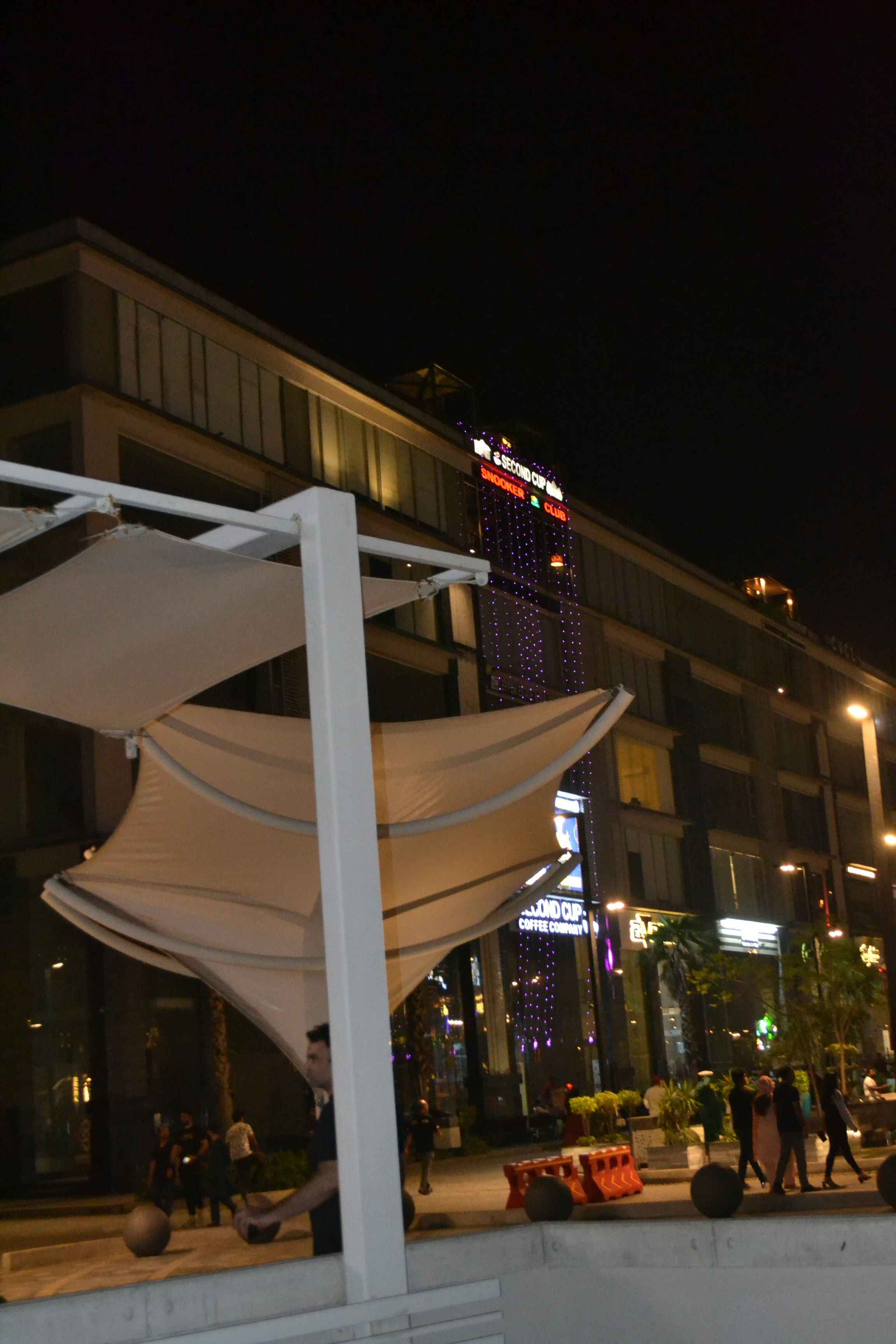 Neon-String Facade and White Canopy: Nightlife at the Glass-front Plaza
