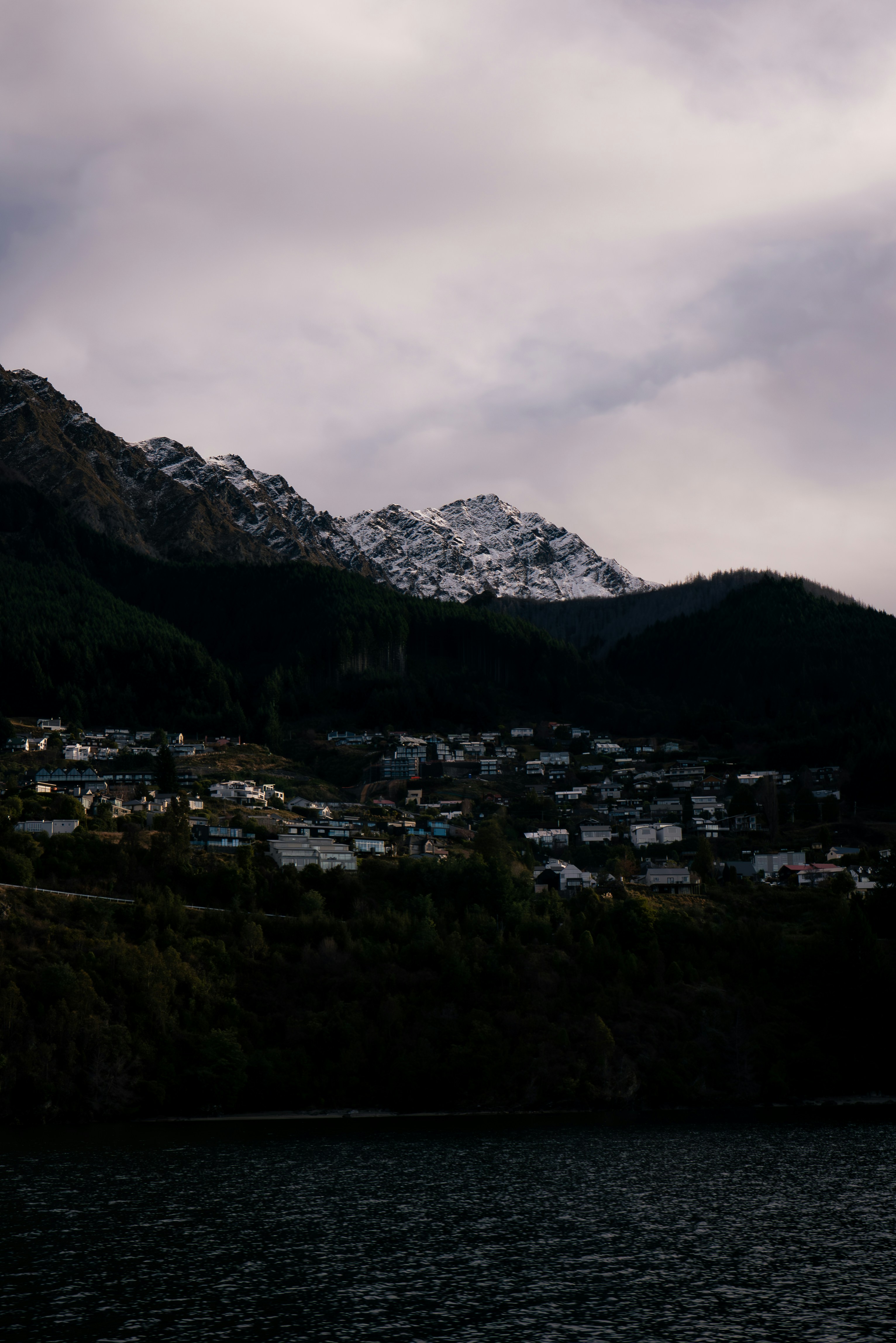 Snow-dusted ridge overlooks a quiet lakeside village at dusk