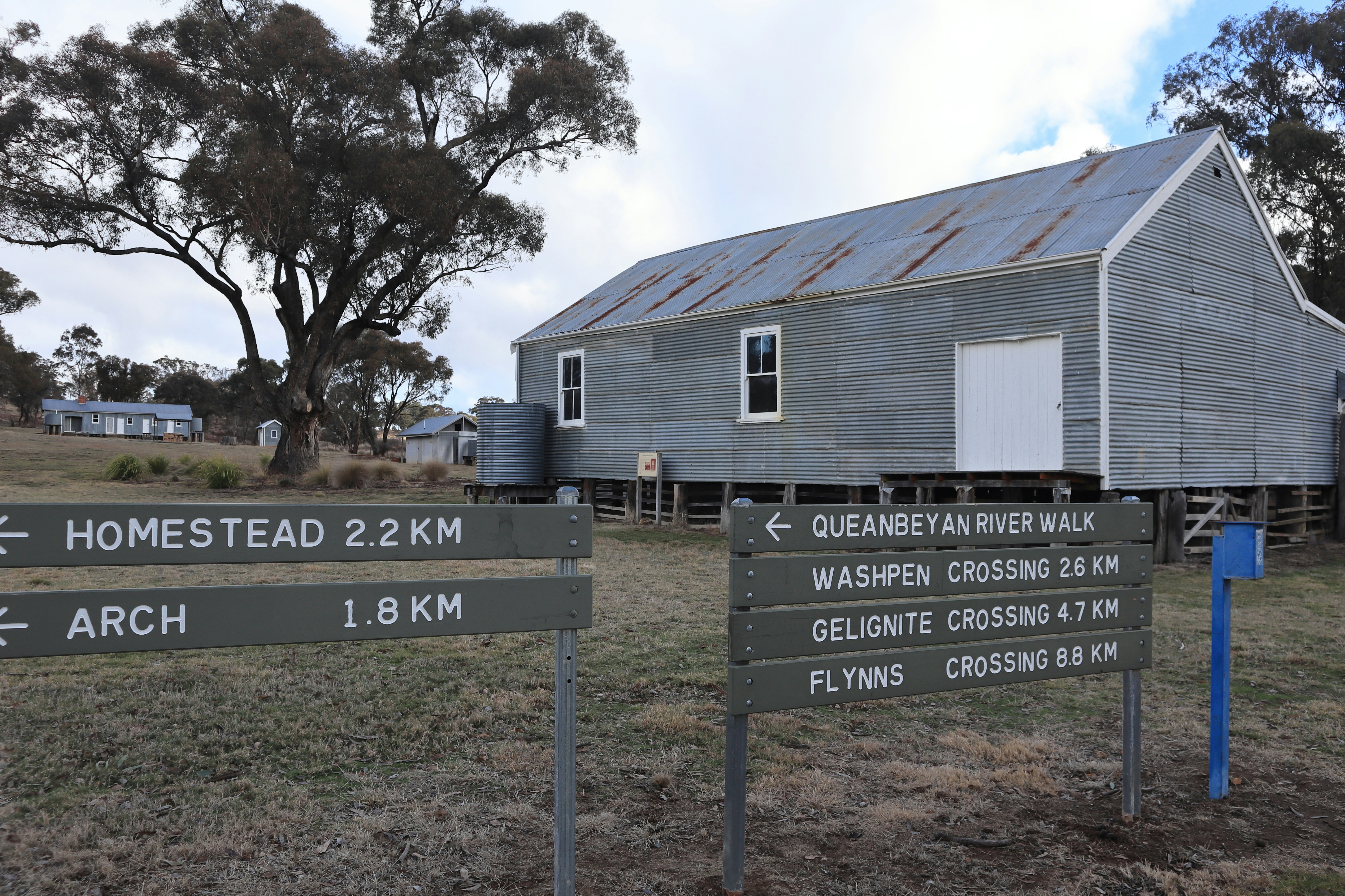 Rust-Laced Crossroads: Signposts Stand Guard by a Corrugated Shed