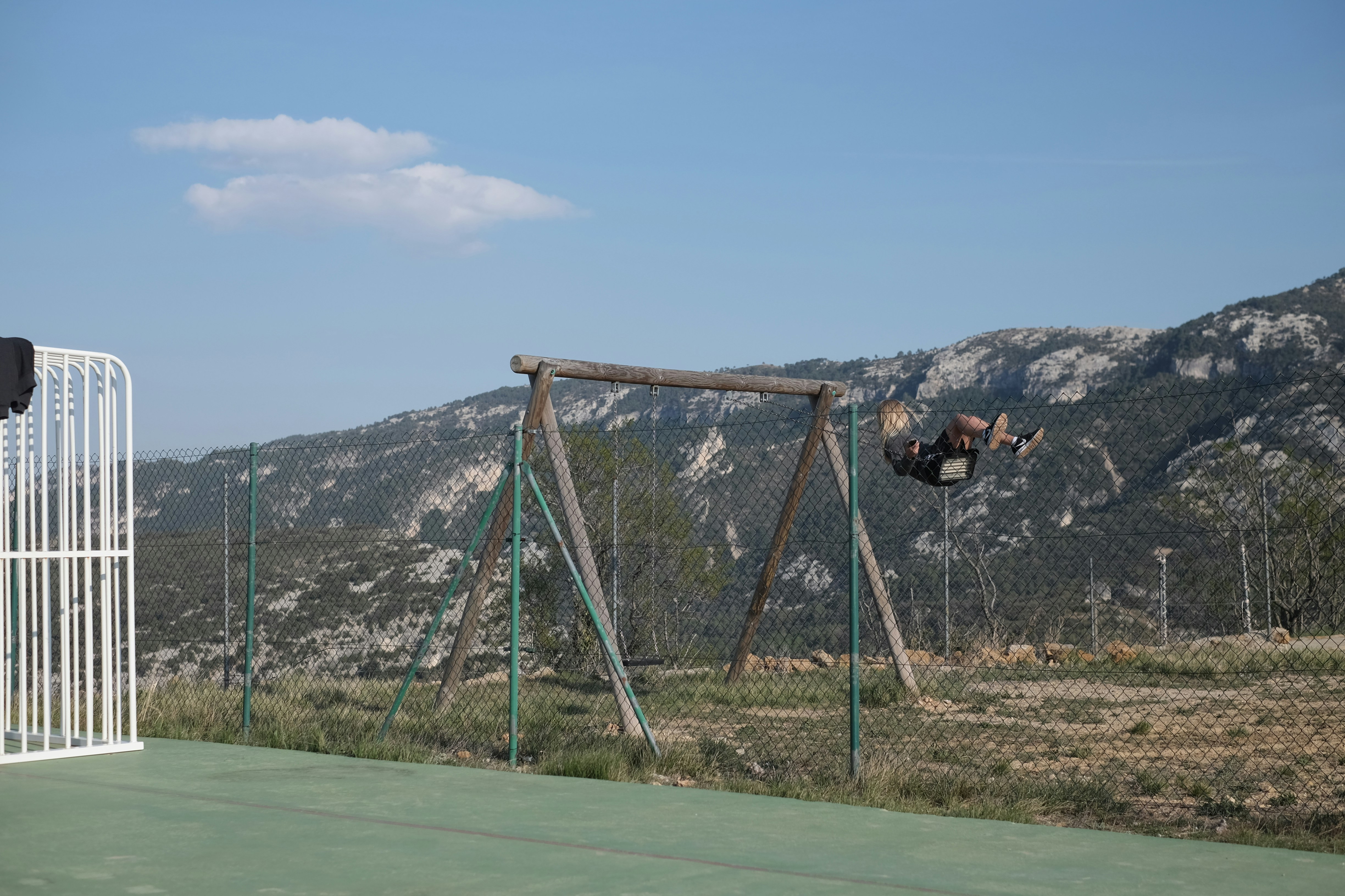 Suspended Rider Over a Green Court Against a Rugged Mountain Backdrop