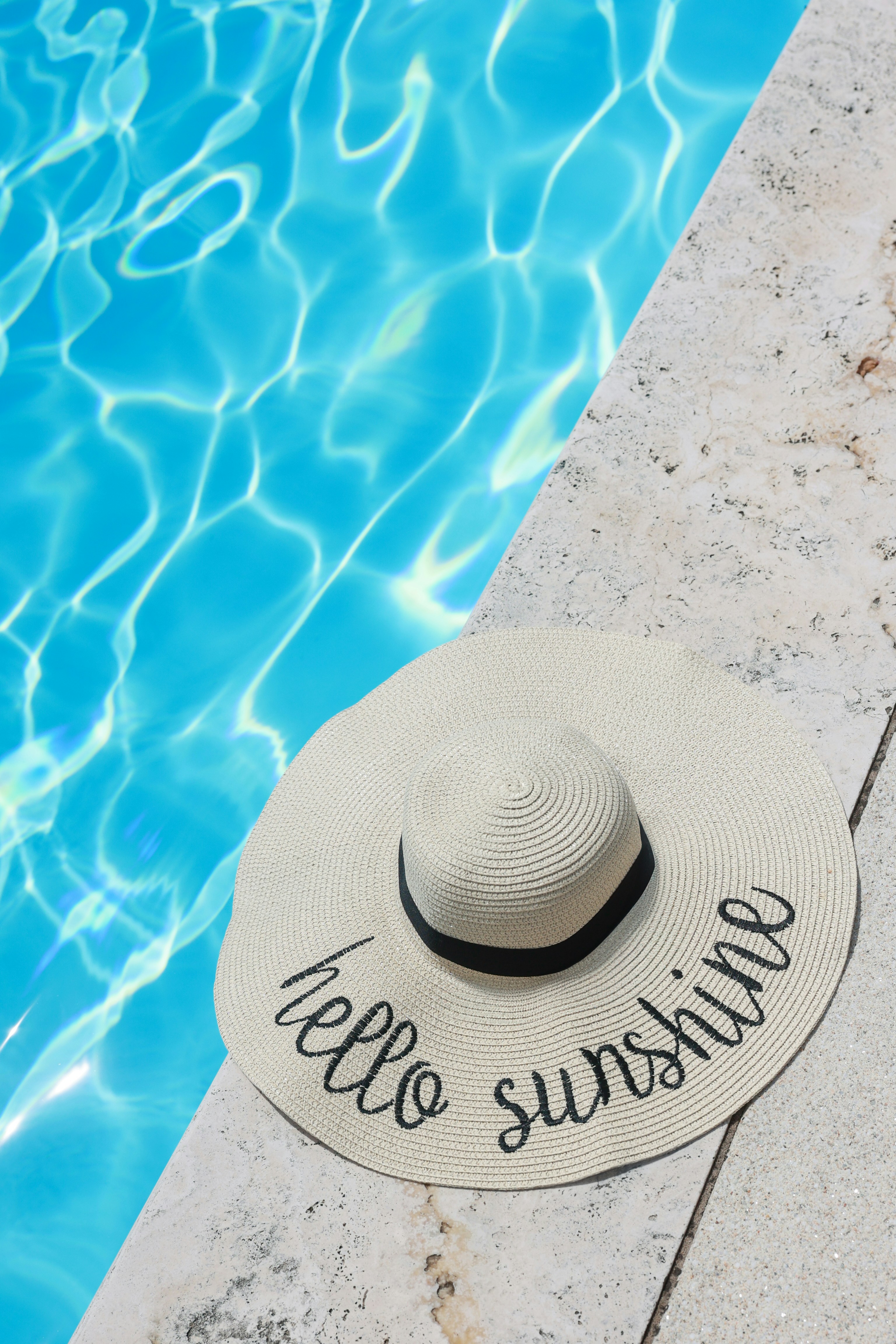 Hello Sunshine at the Pool Edge: A Sun Hat Beside Turquoise Water