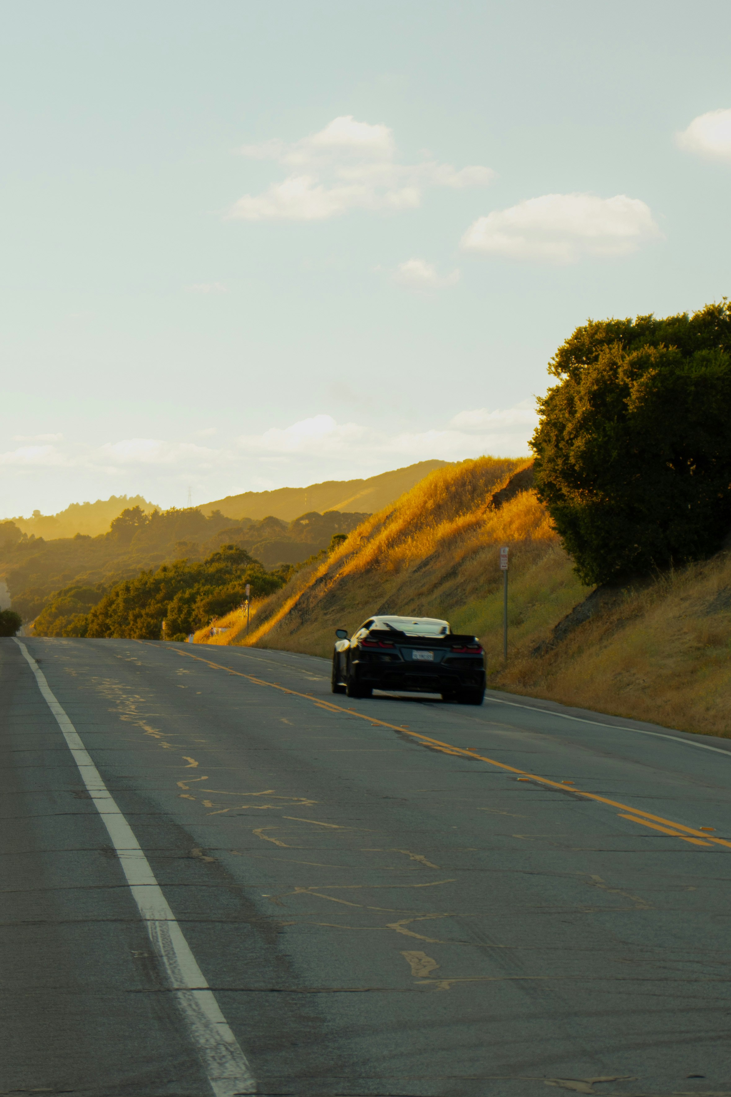 Un'auto che percorre una strada accanto a una collina verde ...