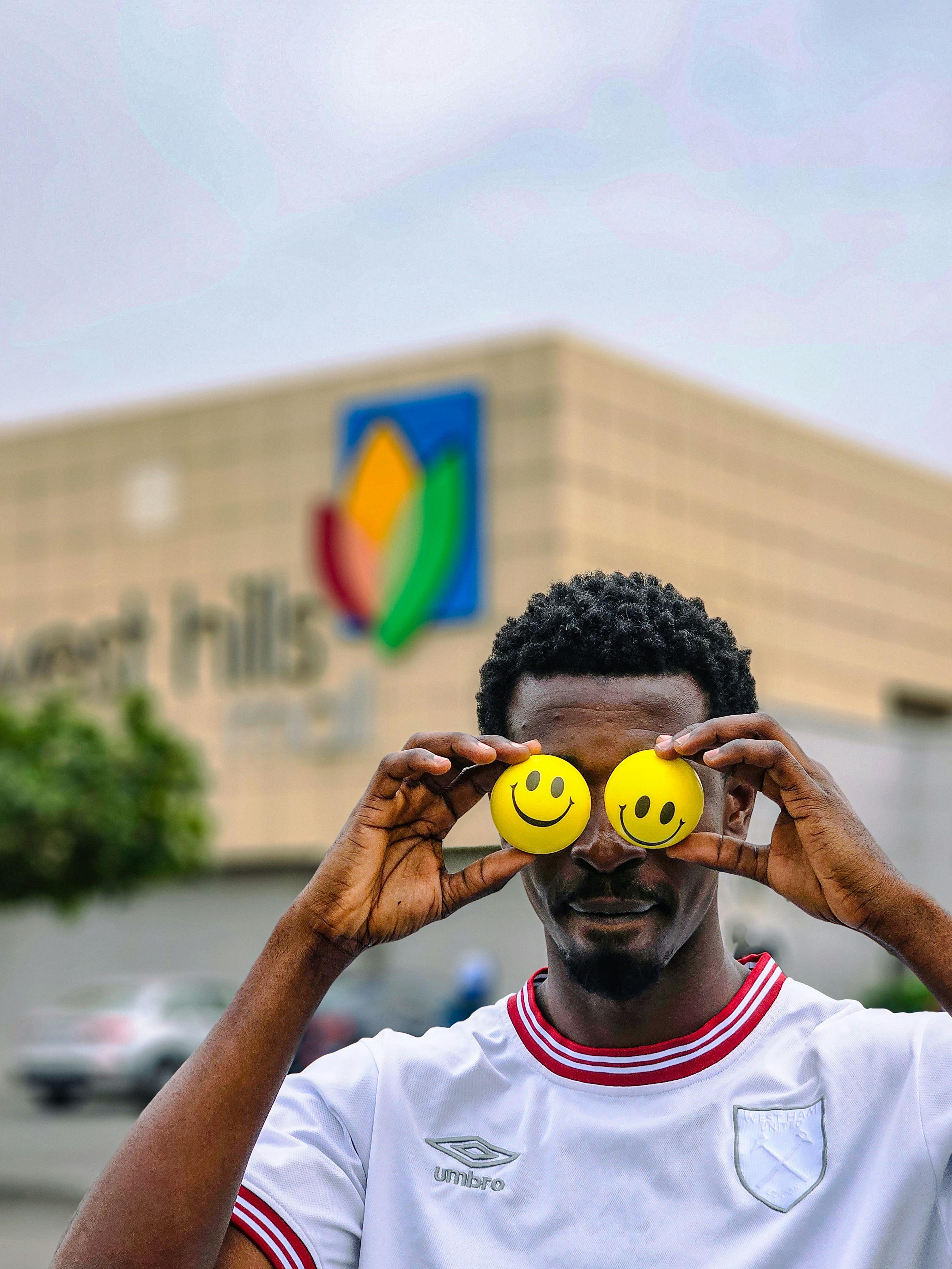 A man holding two smiley faces in front of his eyes photo – Free Fun ...