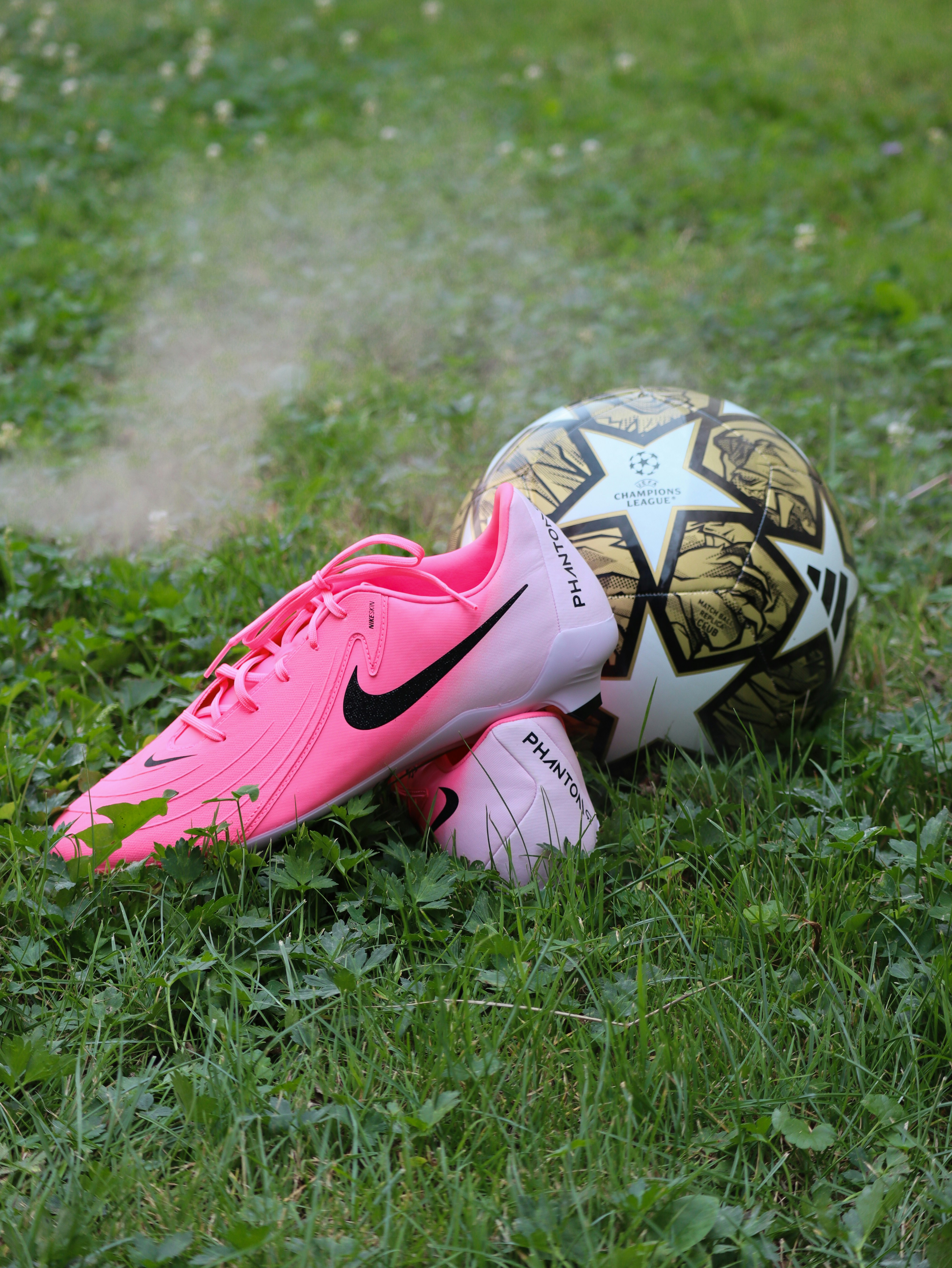 Neon Pink Cleats Resting Against a Star Ball on Grassy Field