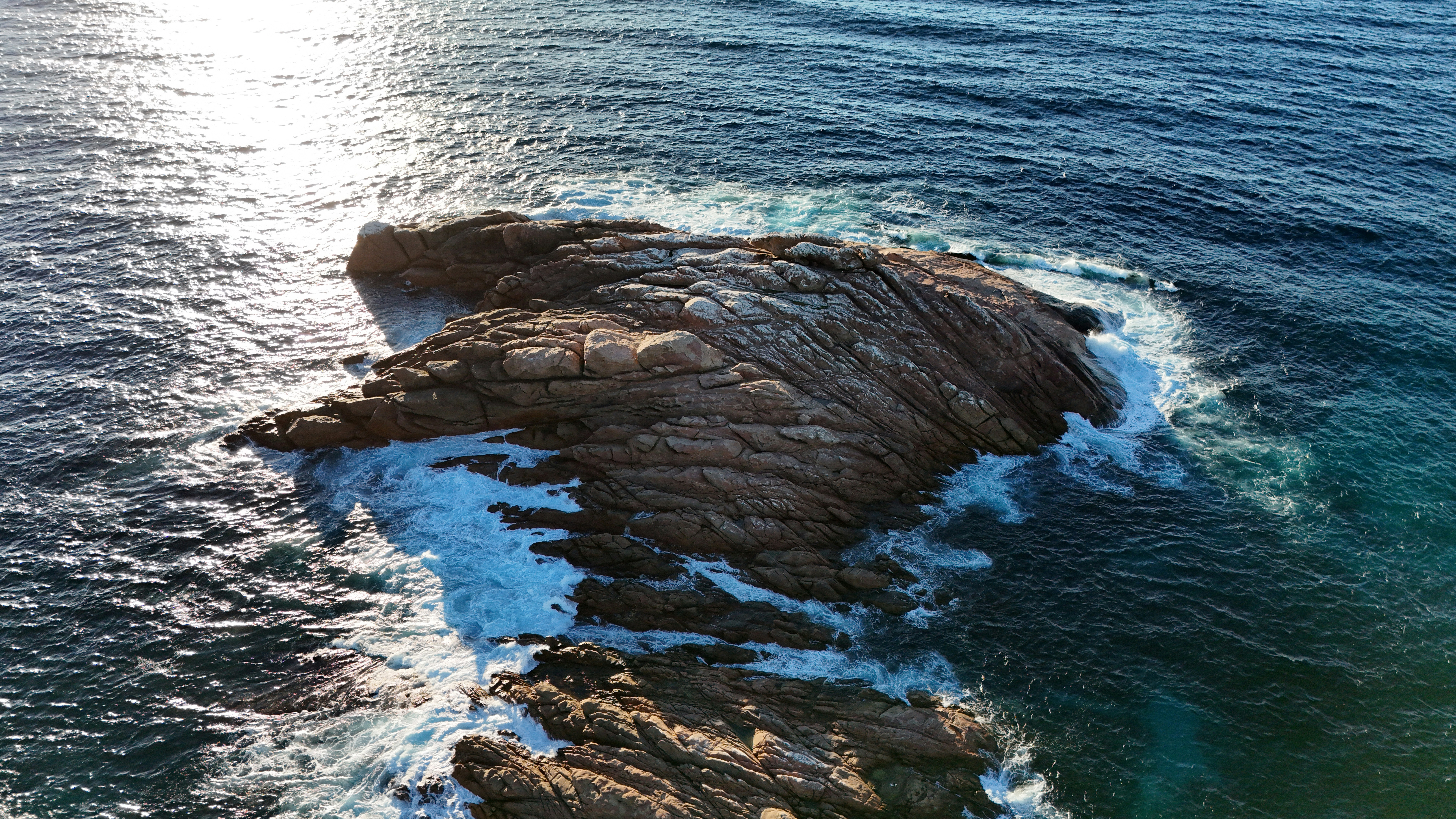 Rocky Promontory Piercing the Sea as Sunlit Currents Sparkle