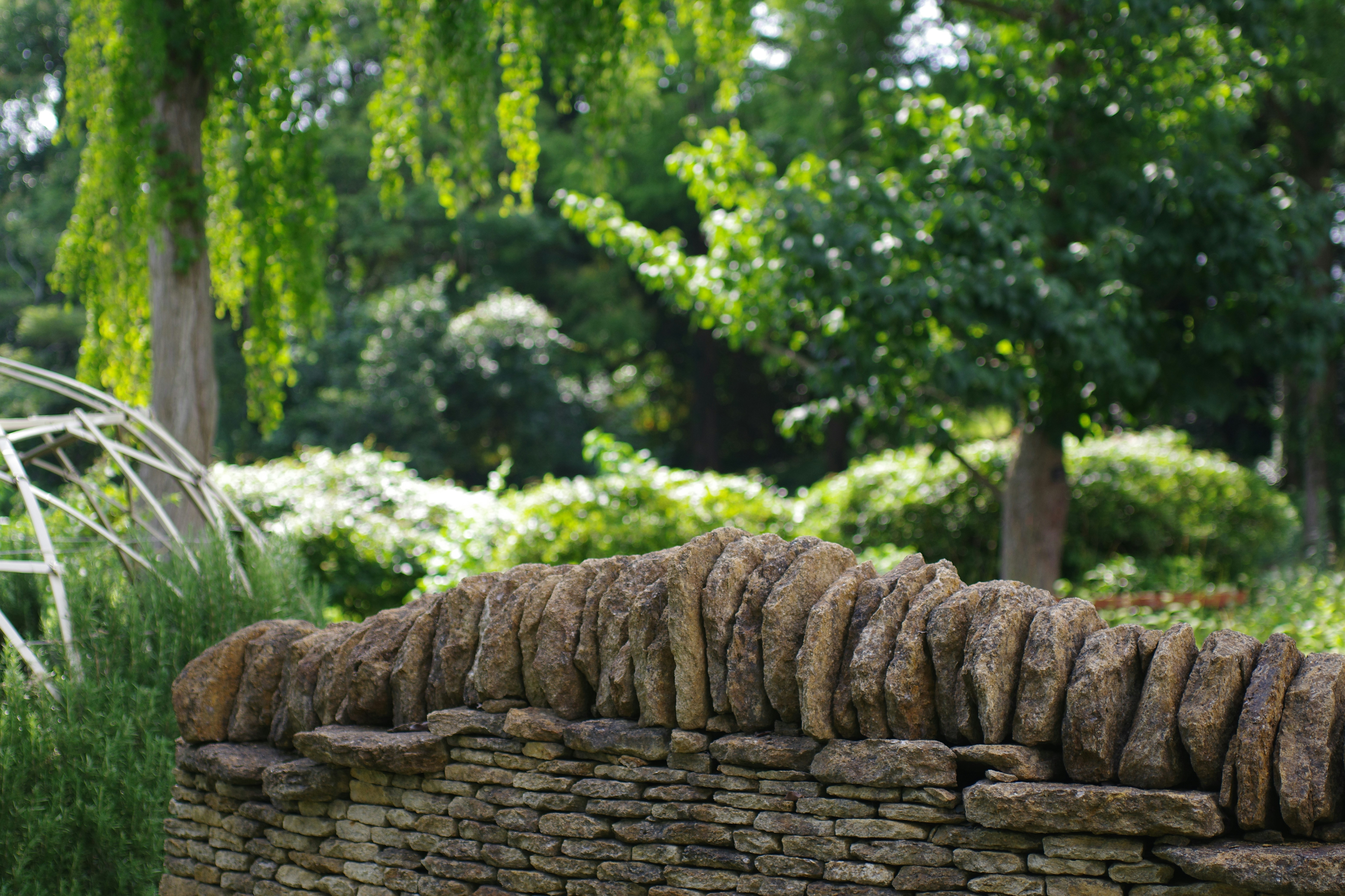 Stone-Stacked Garden Wall Under Dappled Greenery