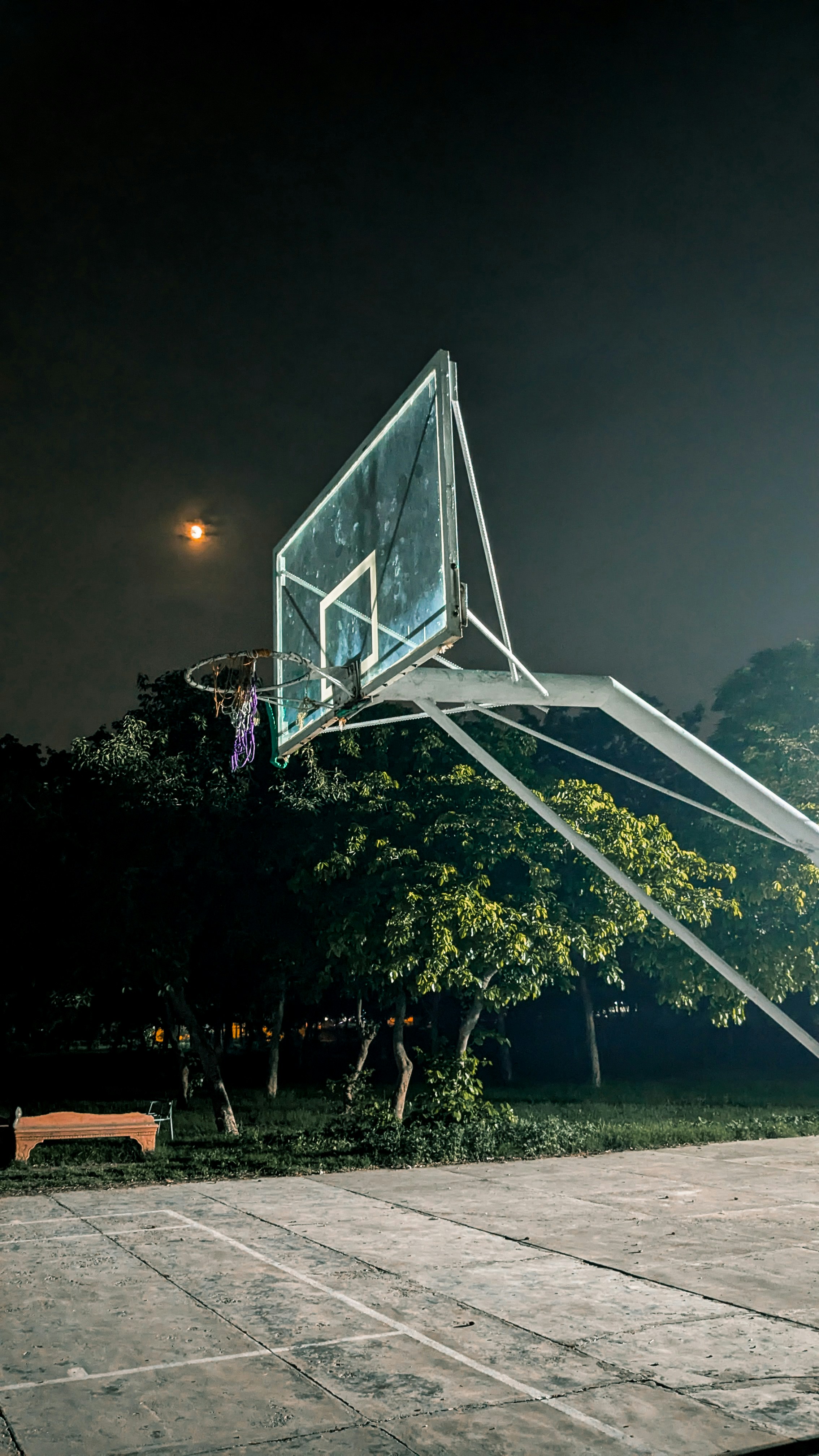 Nocturnal Hoop: A Tilted Backboard Reaches for the Moonlit Sky