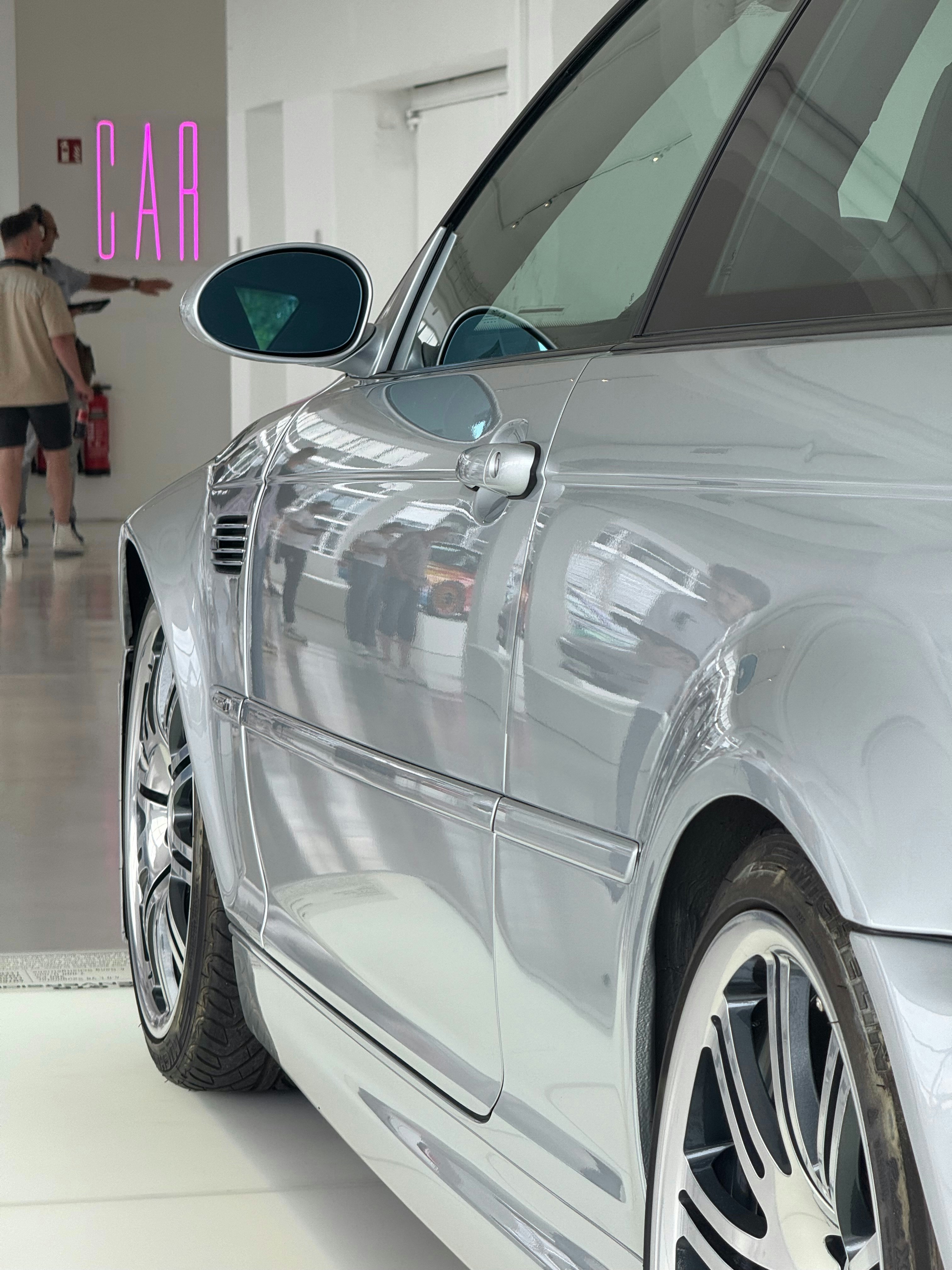 Chrome Mirror: A Silver Sedan Reflects a Quiet Showroom Scene