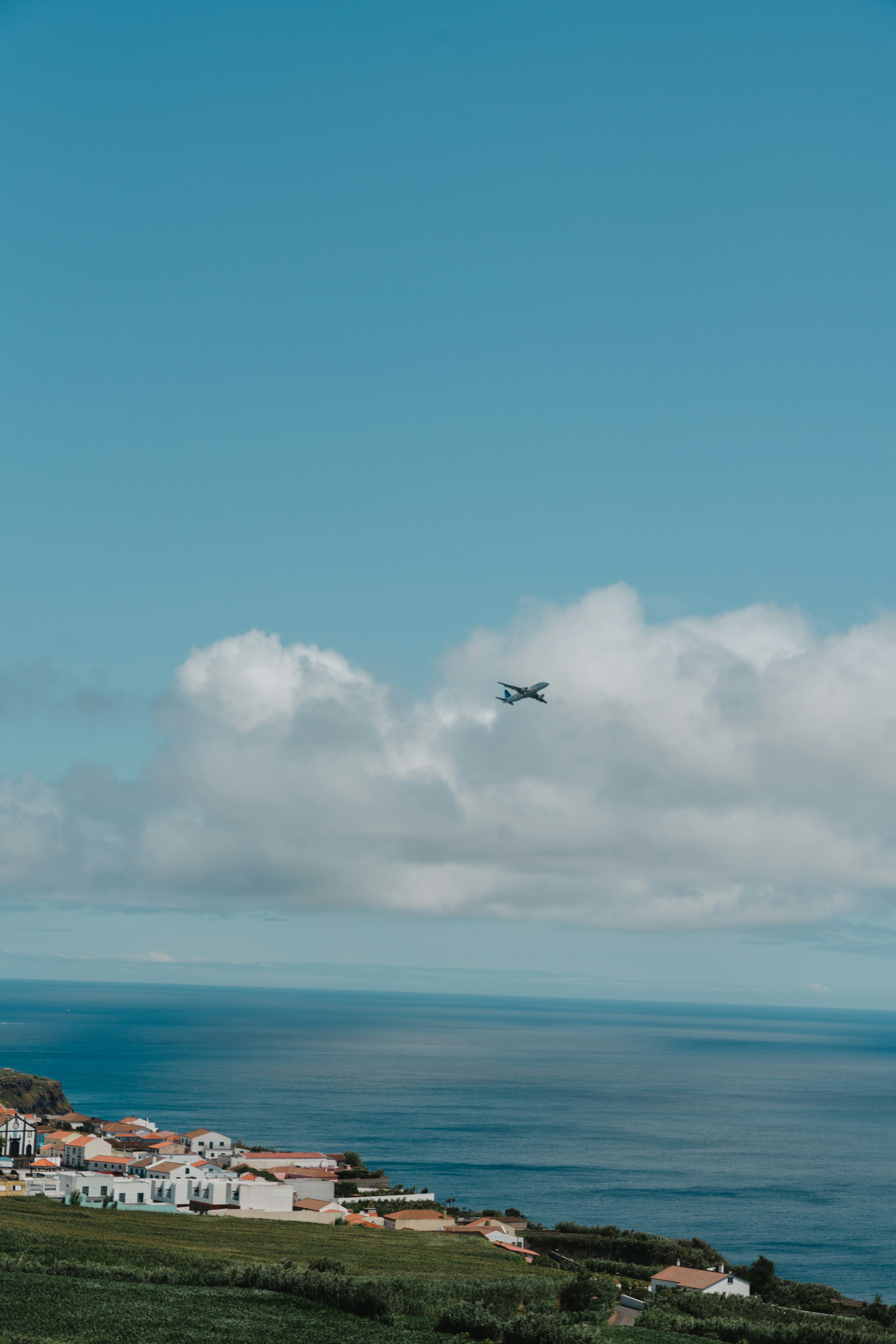 An airplane flying over a small town by the ocean photo – Free Building ...