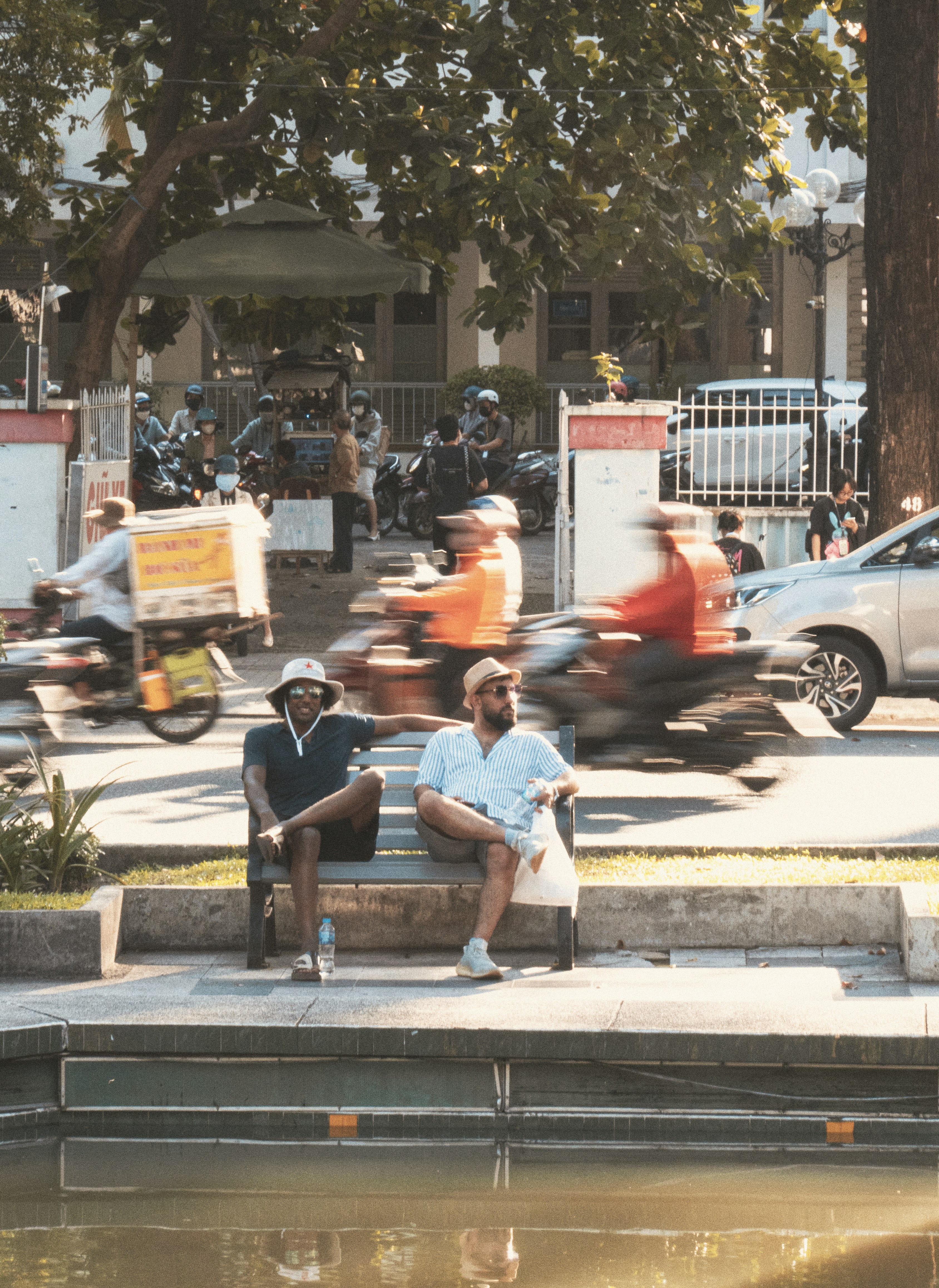 Two men sitting on a bench in front of a body of water