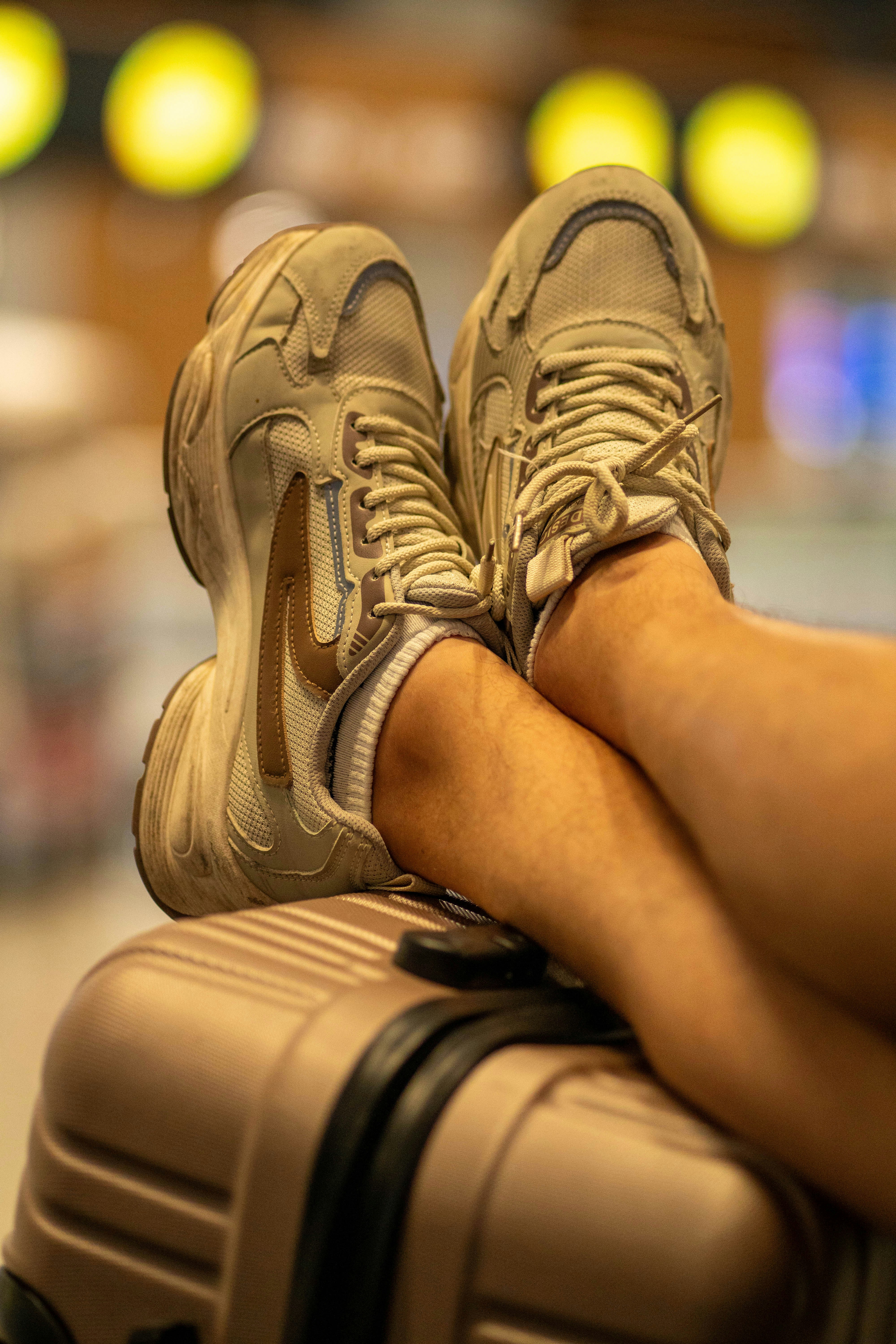 Quiet Terminal: Sneakers Resting on a Luggage Stack Under Golden Lights