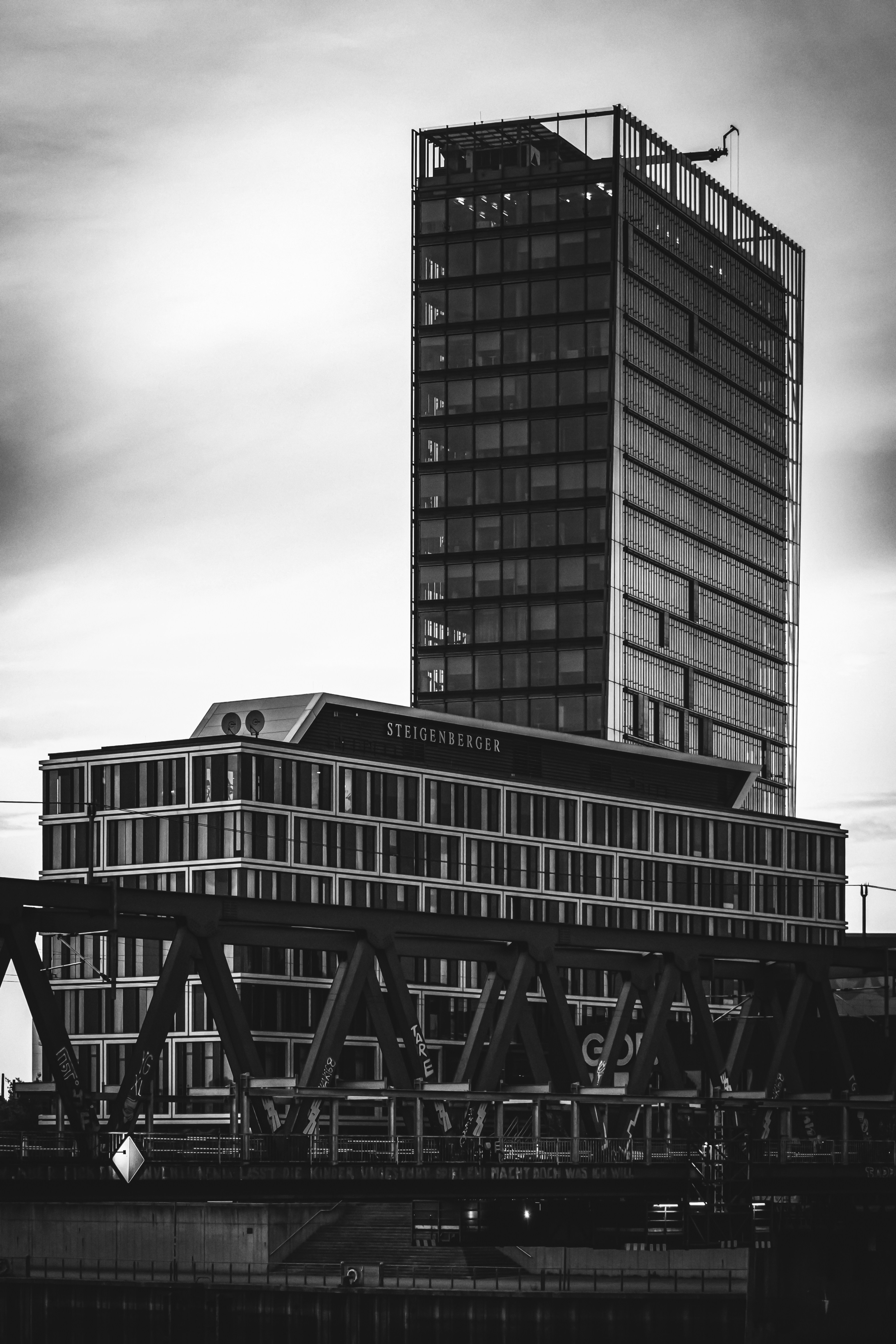 Glass Tower Over Rails: A Monochrome Riverfront Skyline
