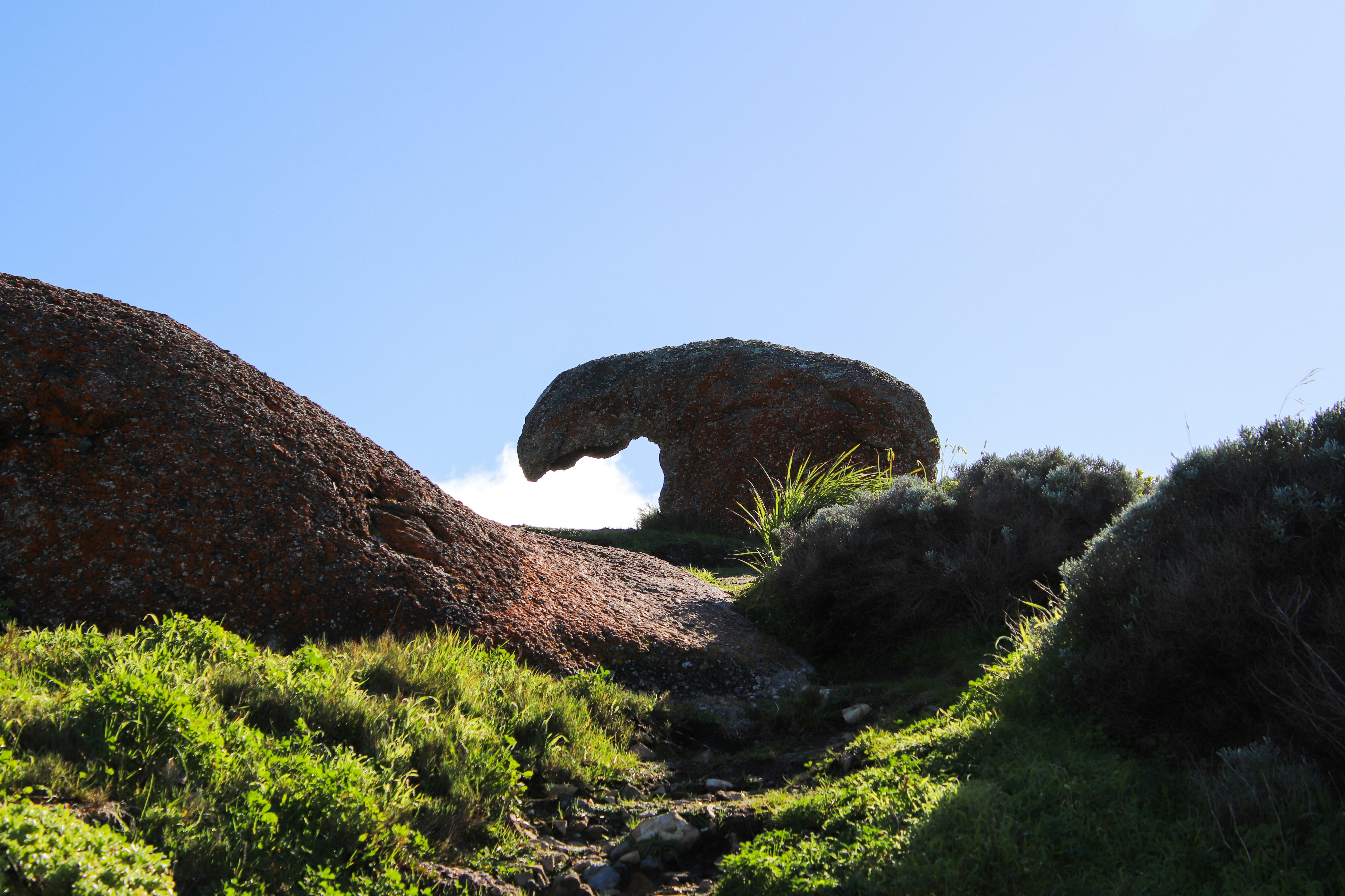 Stone Arch of Sea Breeze: A Curved Rock Gate against a Bright Blue Sky