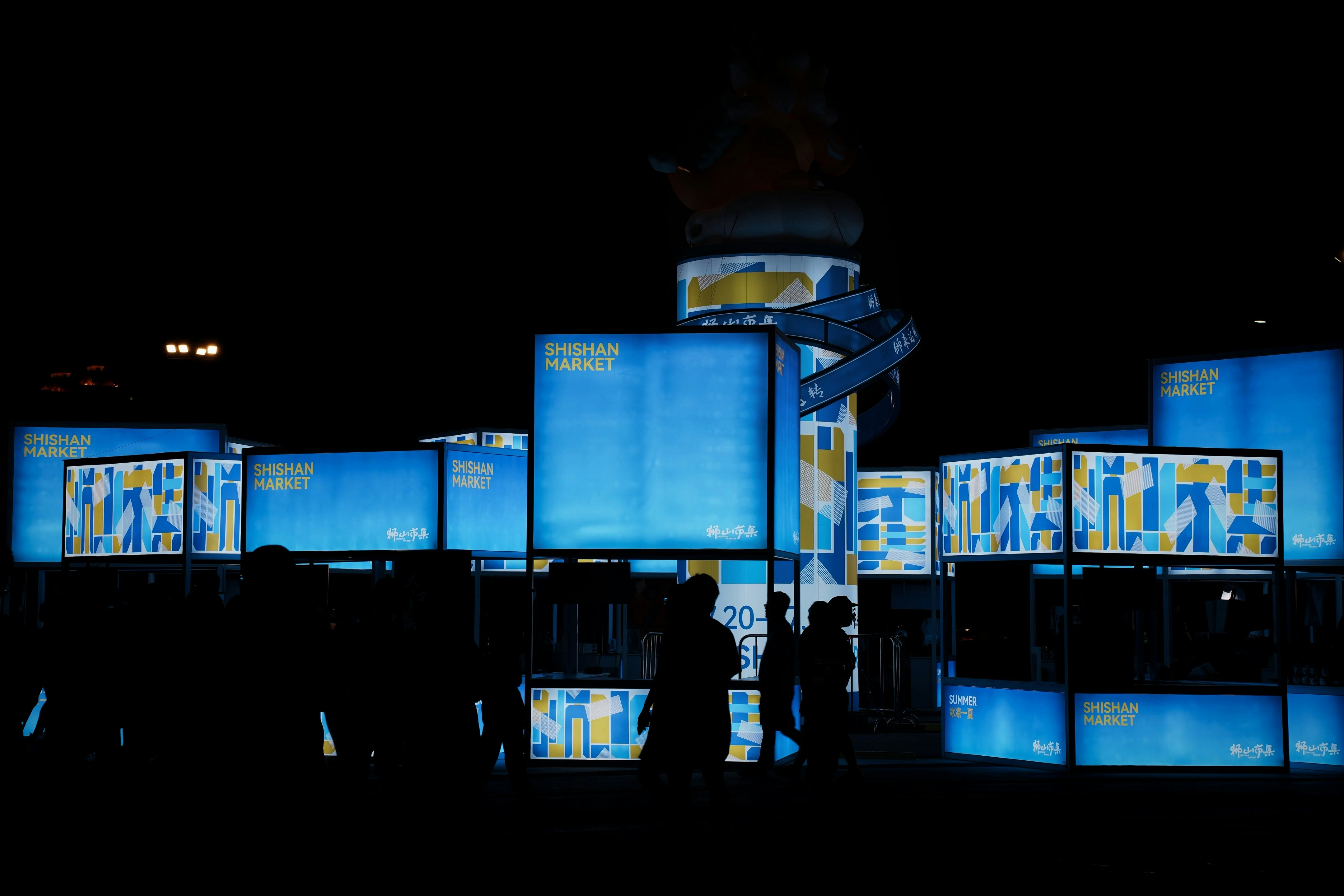 A group of people standing in front of a large display of television ...