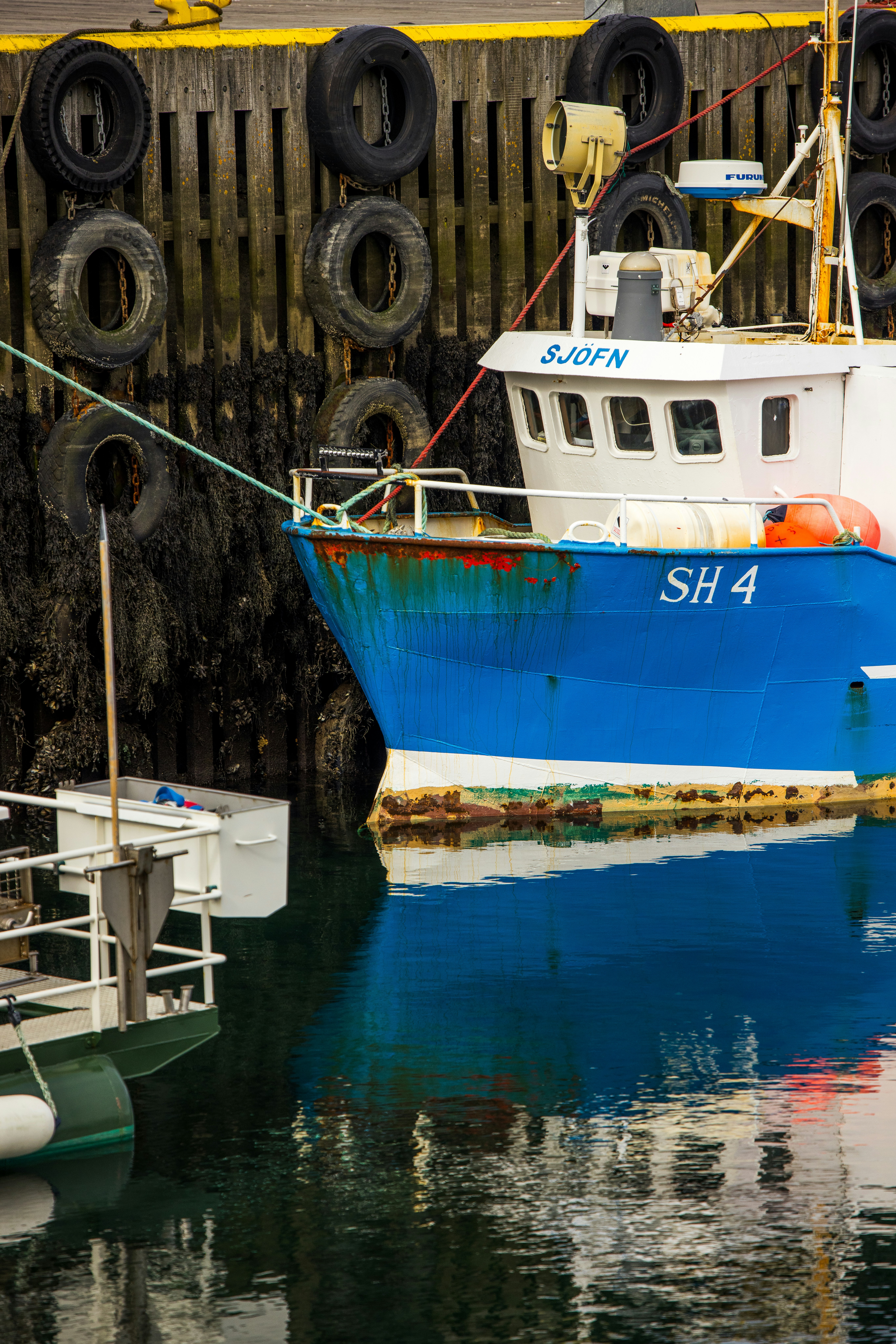 Blue-hulled Vessel at Dock: Reflections and Ropes in a Quiet Harbor