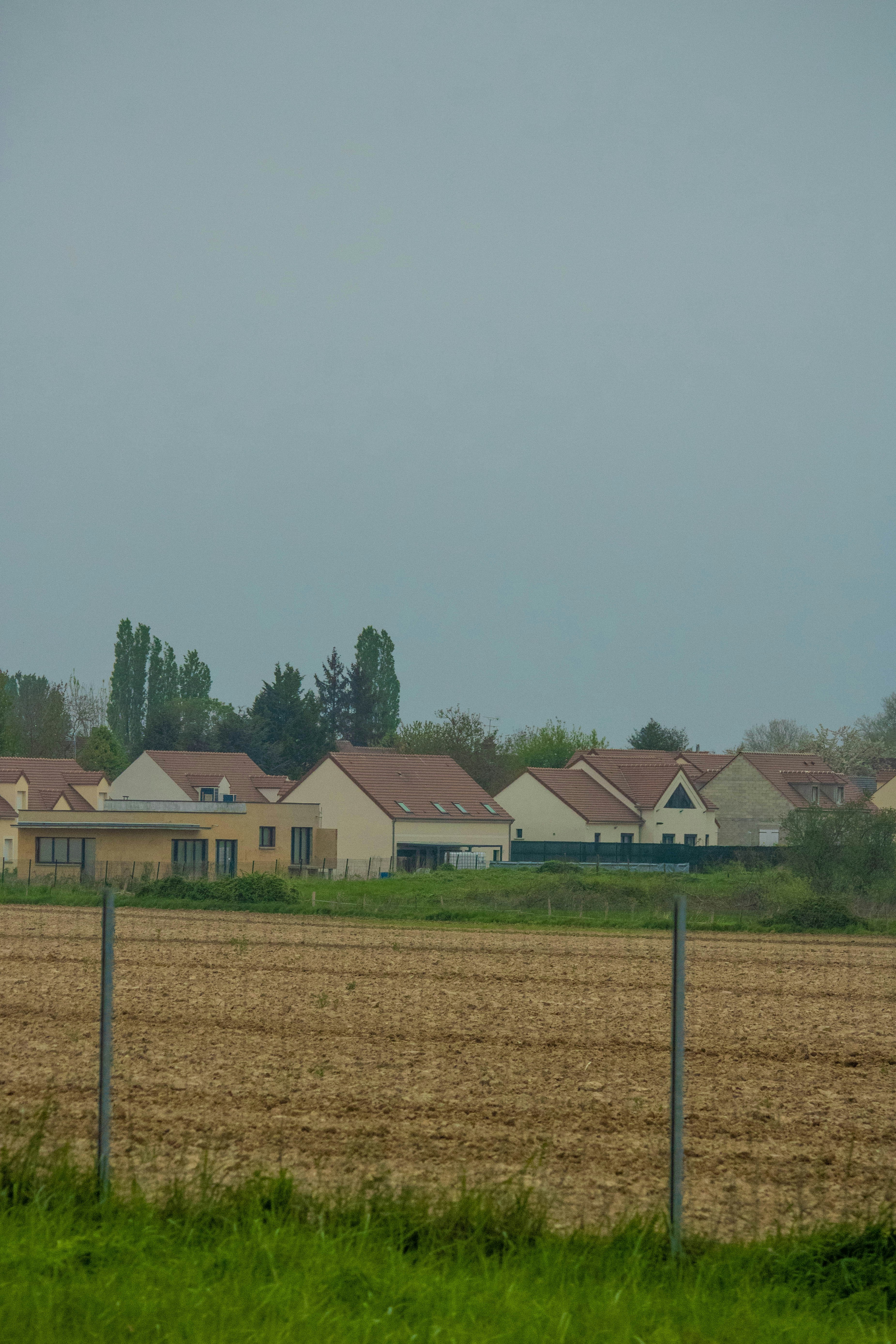 A row of houses in the distance behind a fence photo – Free House Image ...